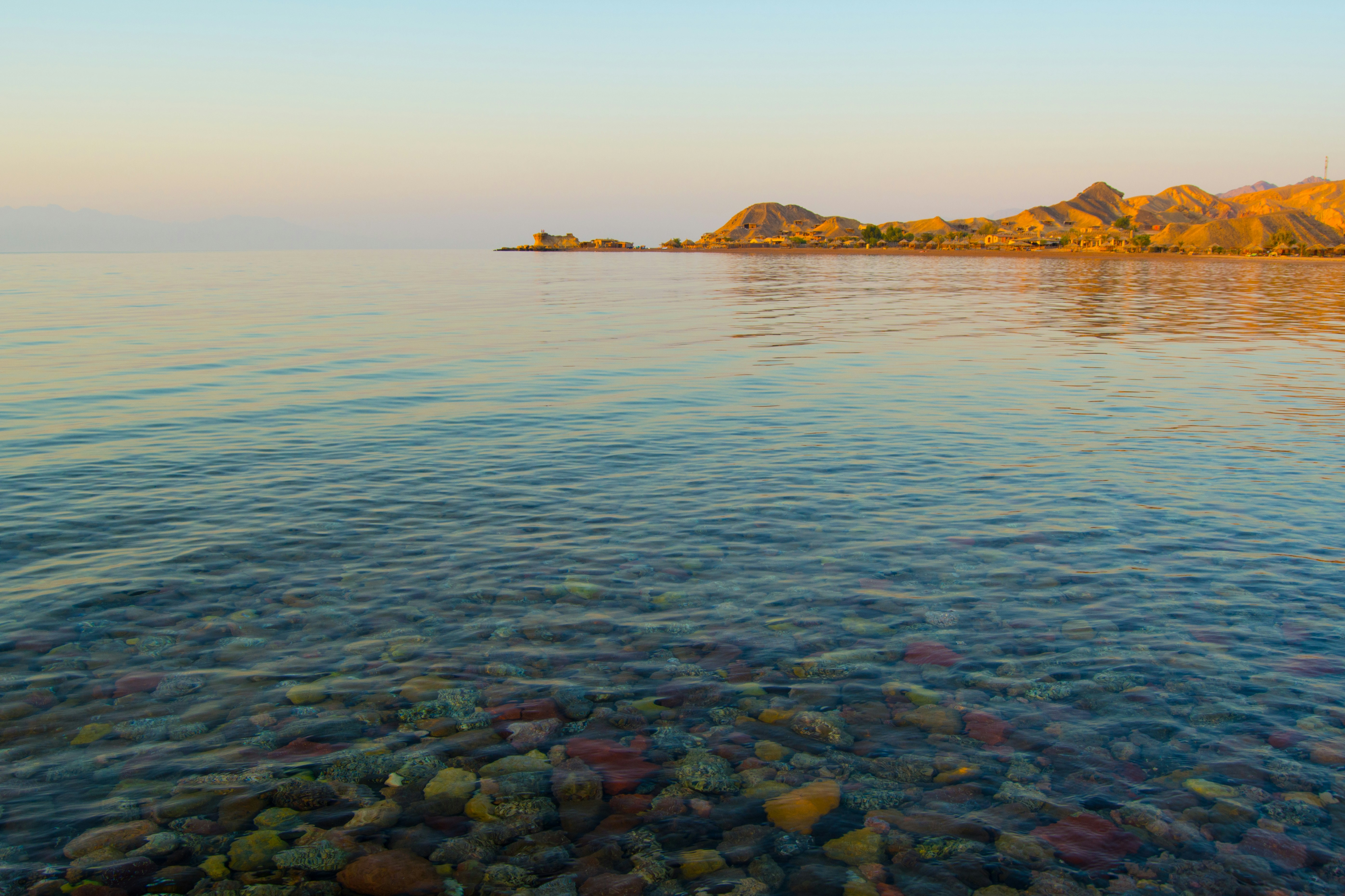 Coastal Calm: Sunlit Rocks Meet Quiet Waters
