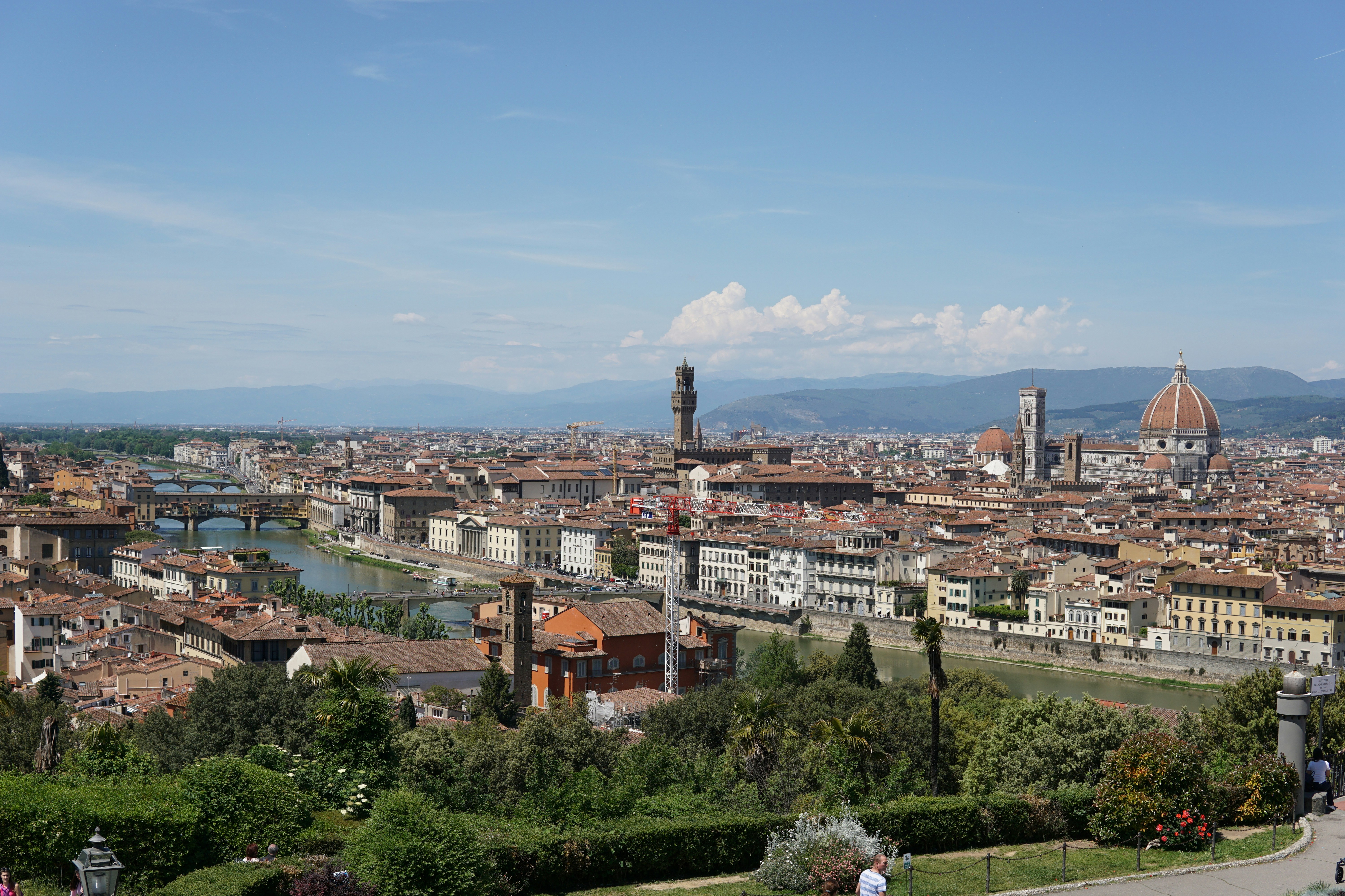 Florence skyline with the Arno River winding through historic architecture and the iconic dome of the Florence Cathedral under a clear sky.
