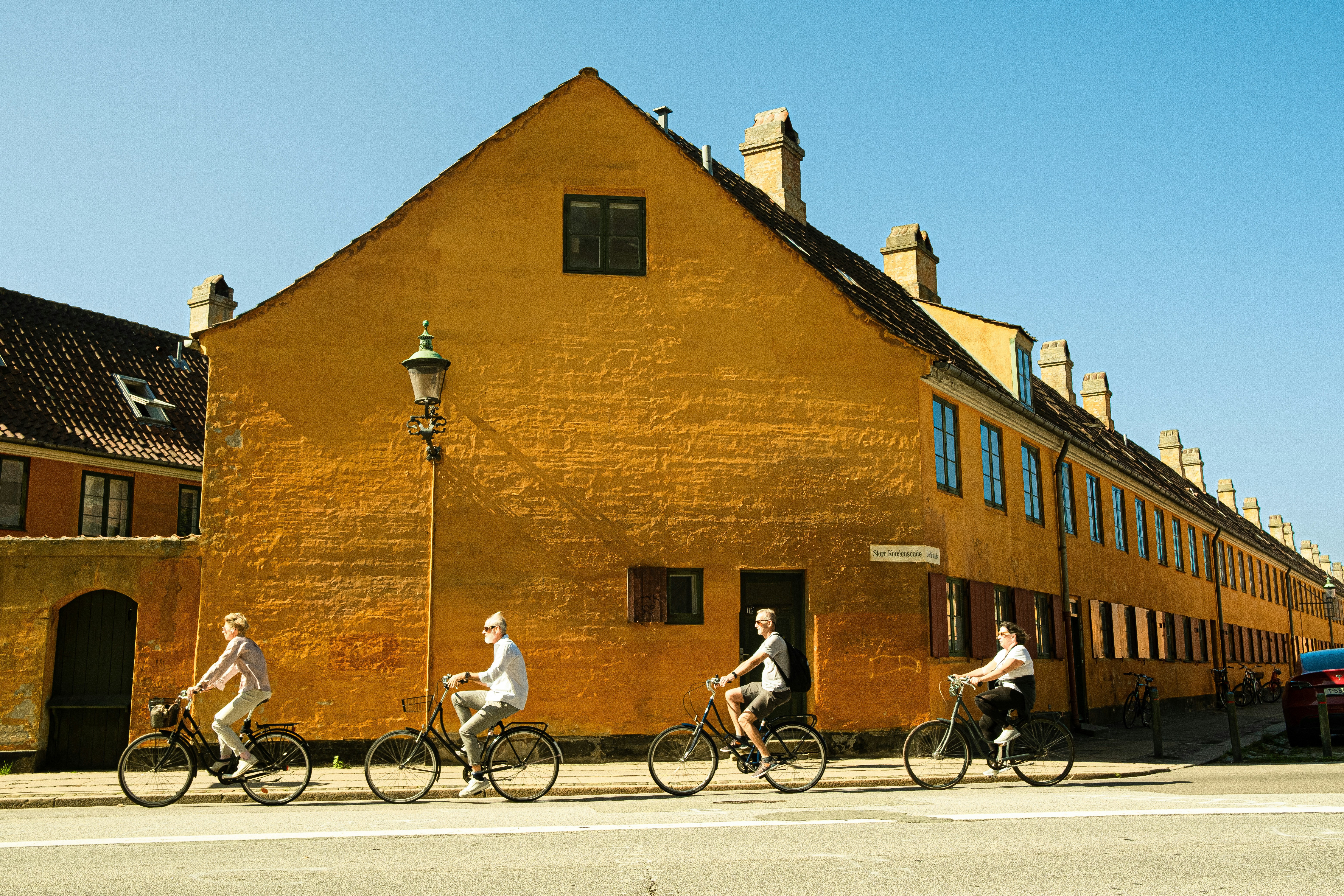 Riders in Front of an Ochre Gable: A Sunlit Street Portrait