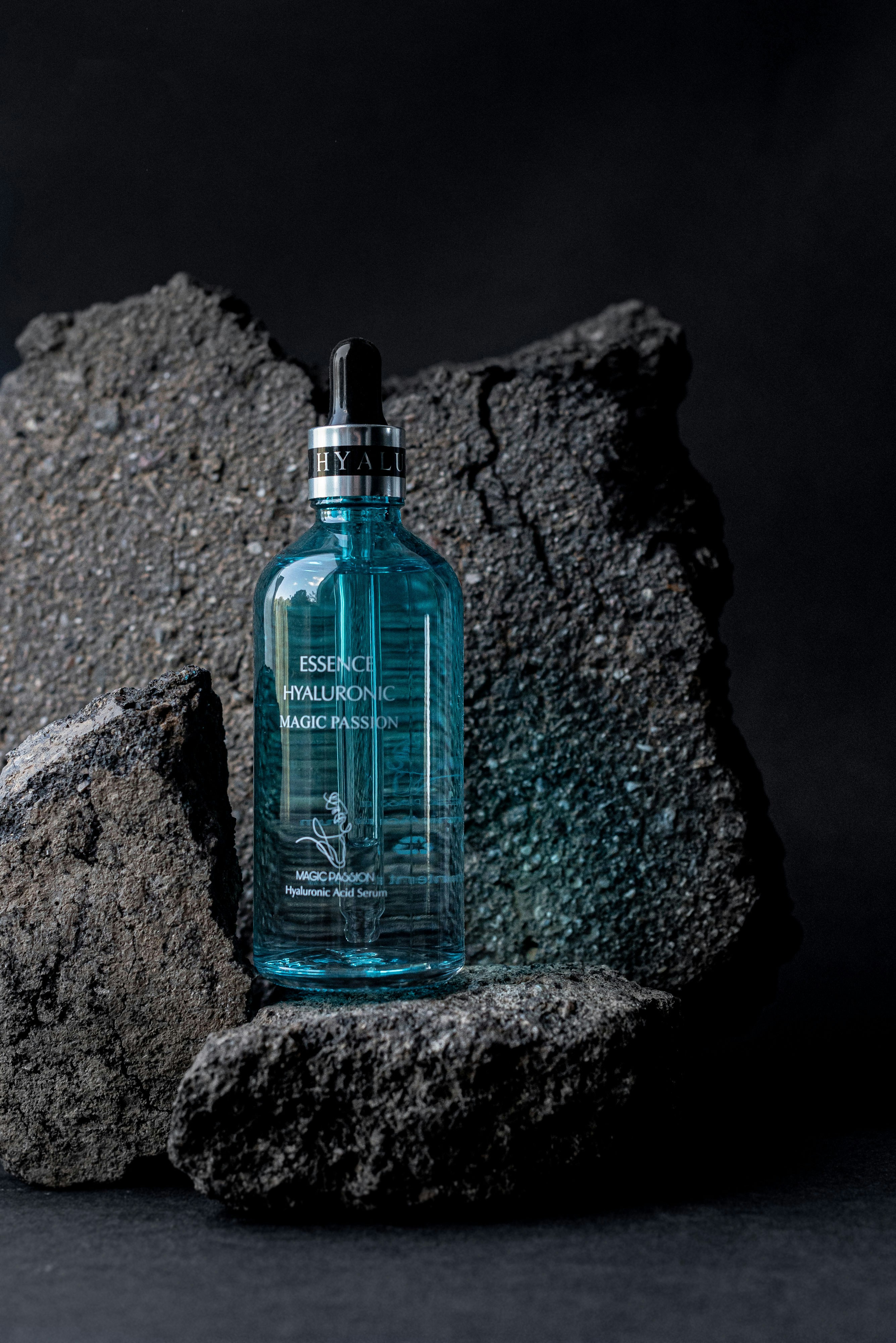 A bottle of cologne sitting on top of a rock photo – Free Cosmetics ...
