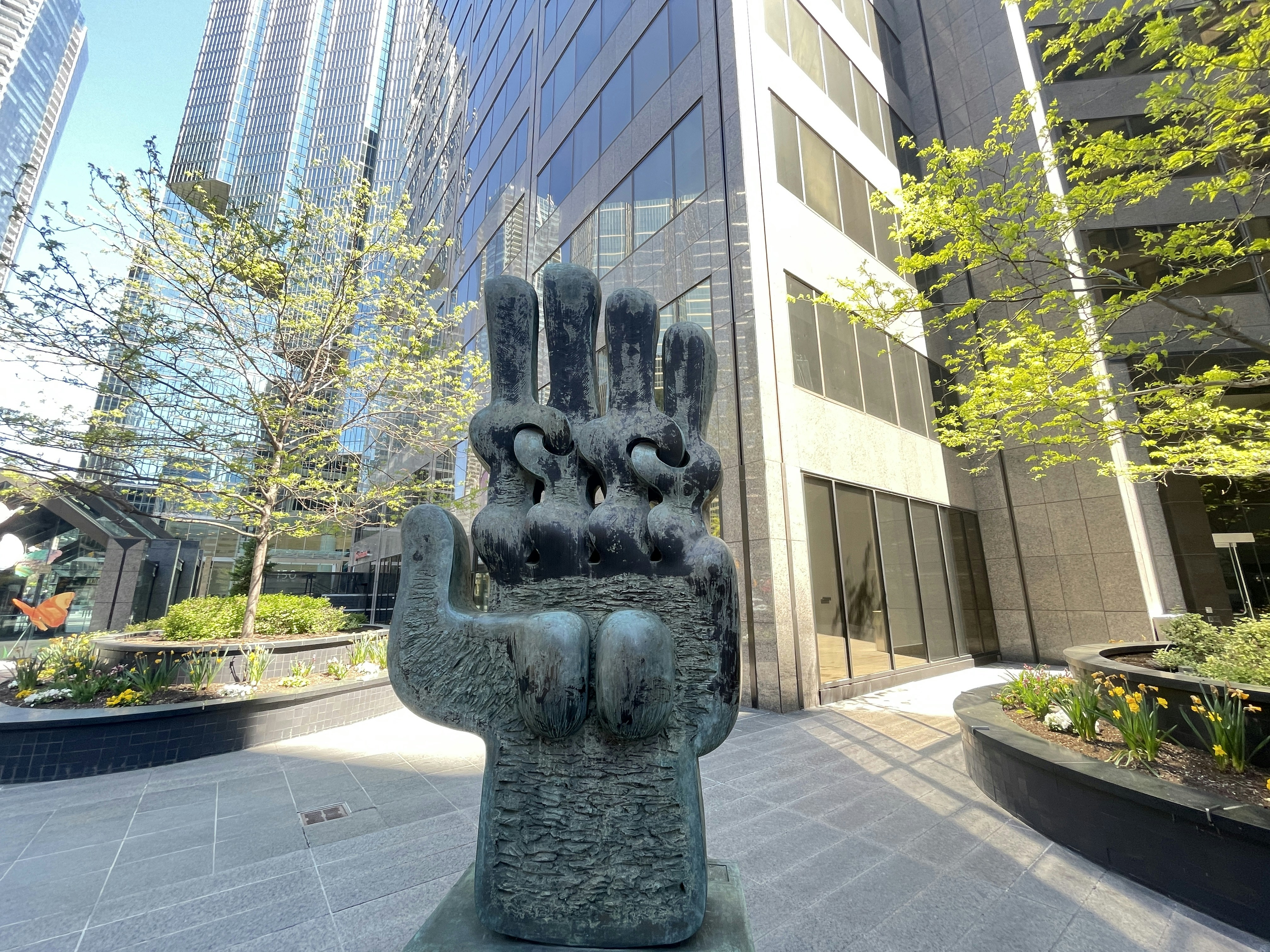 Sculpture of a large hand holding multiple smaller hands in an urban plaza.