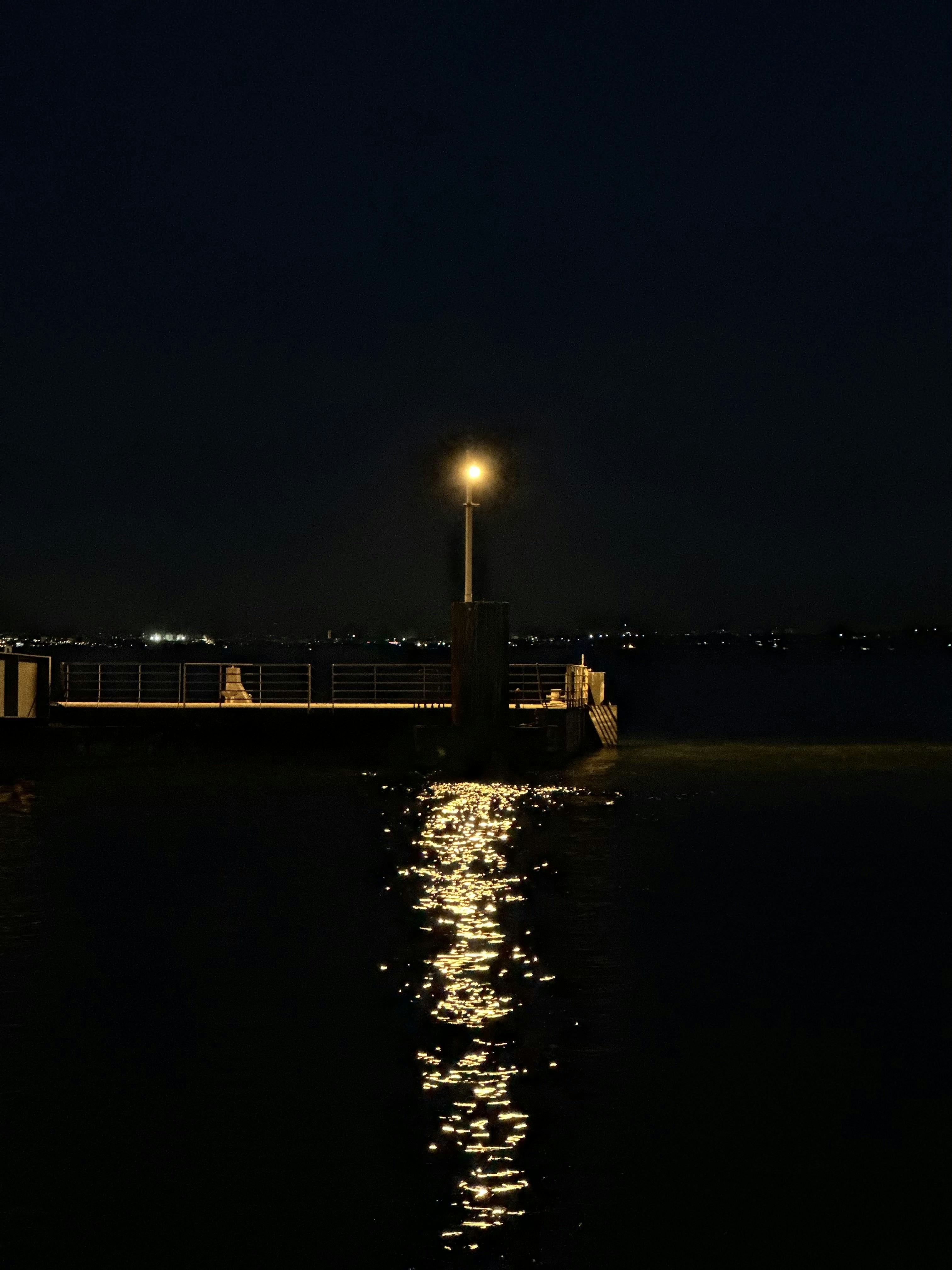 Nocturnal Pier Beacon: Golden Ripples on Velvet Water