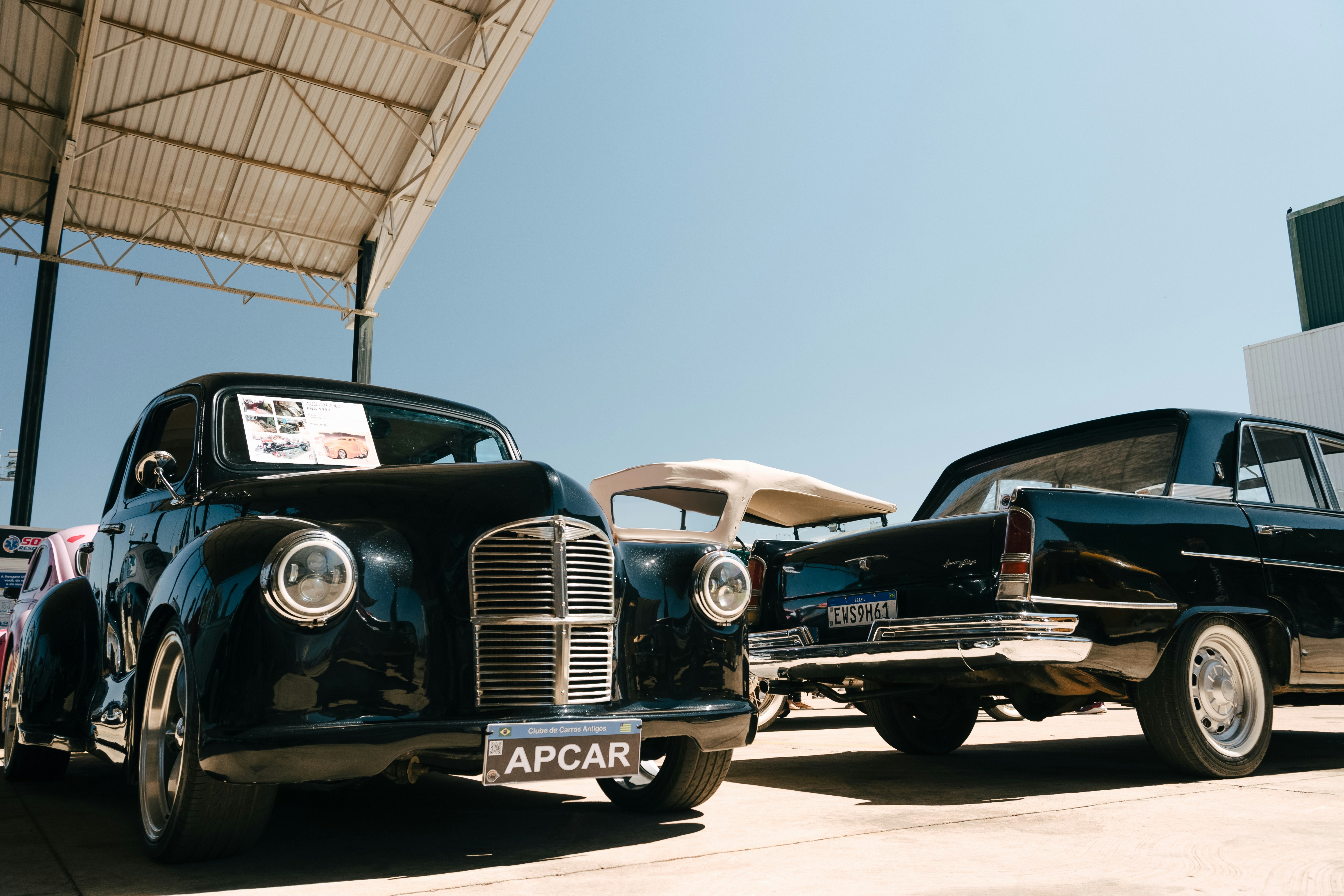 APCAR Under the Canopy: A Black Vintage Sedan at a Sunlit Car Show
