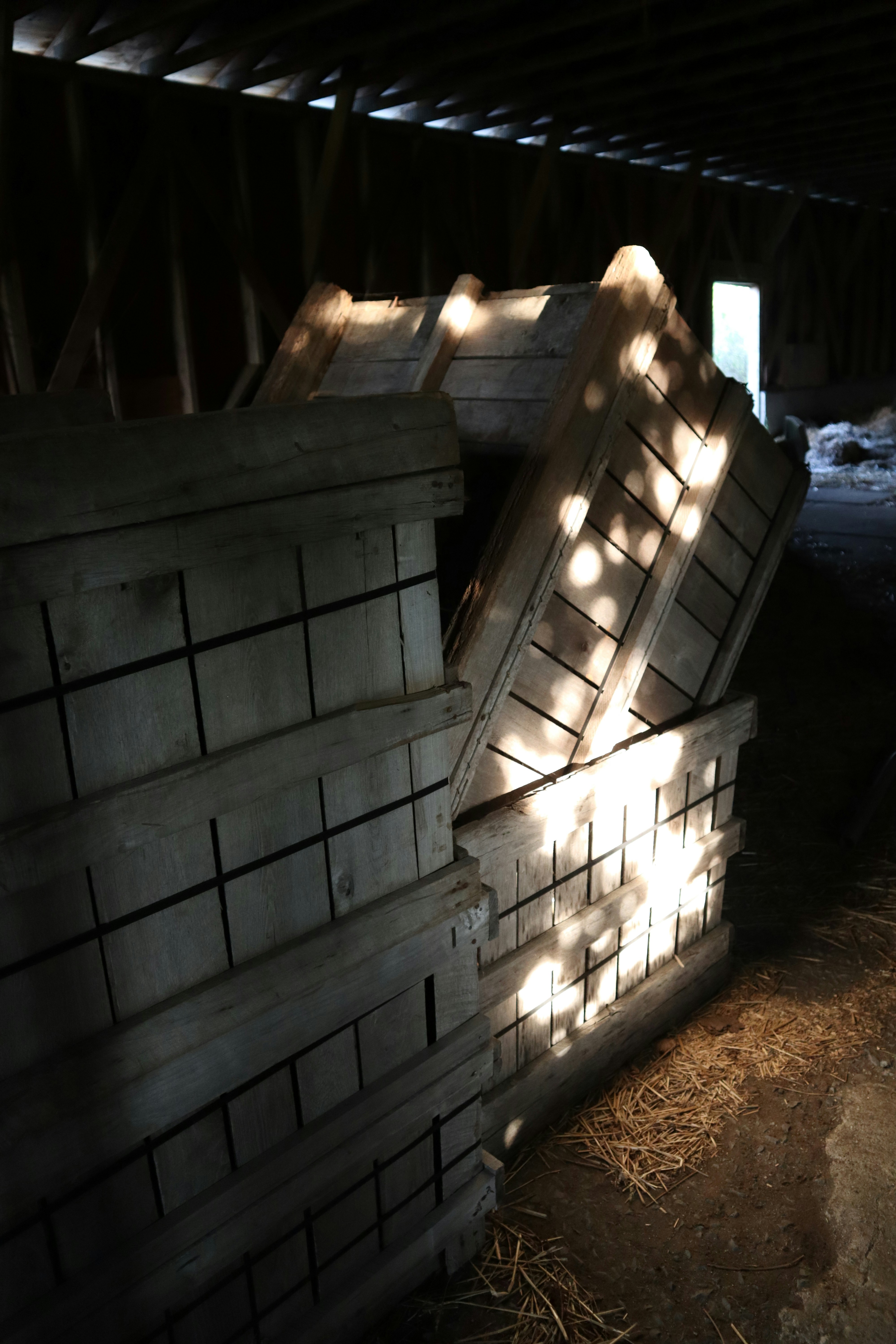 Sunlit Stripes on Weathered Crates Beneath a Dim Barn Roof