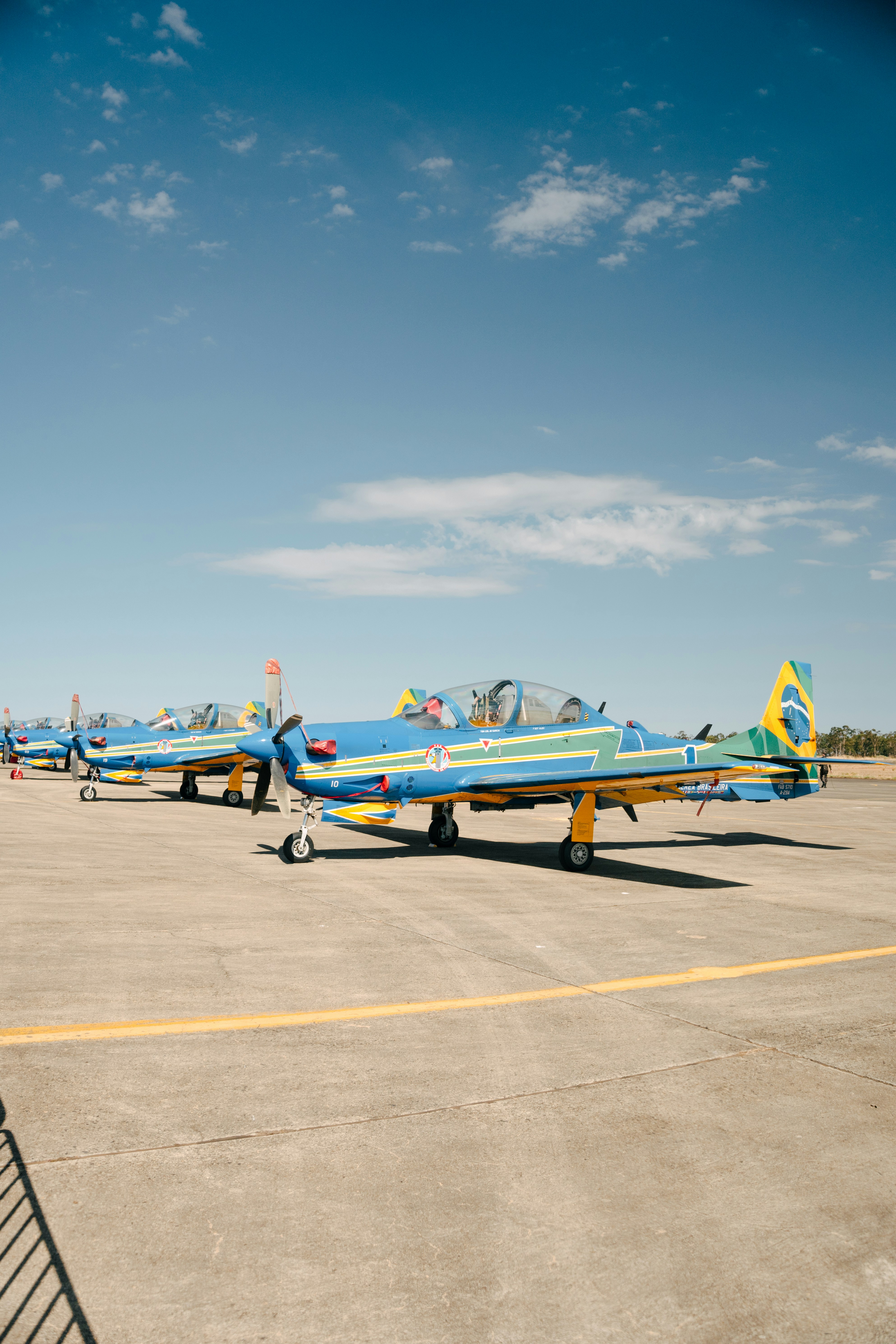 Una fila de aviones azules y amarillos sentados encima de la pista de ...