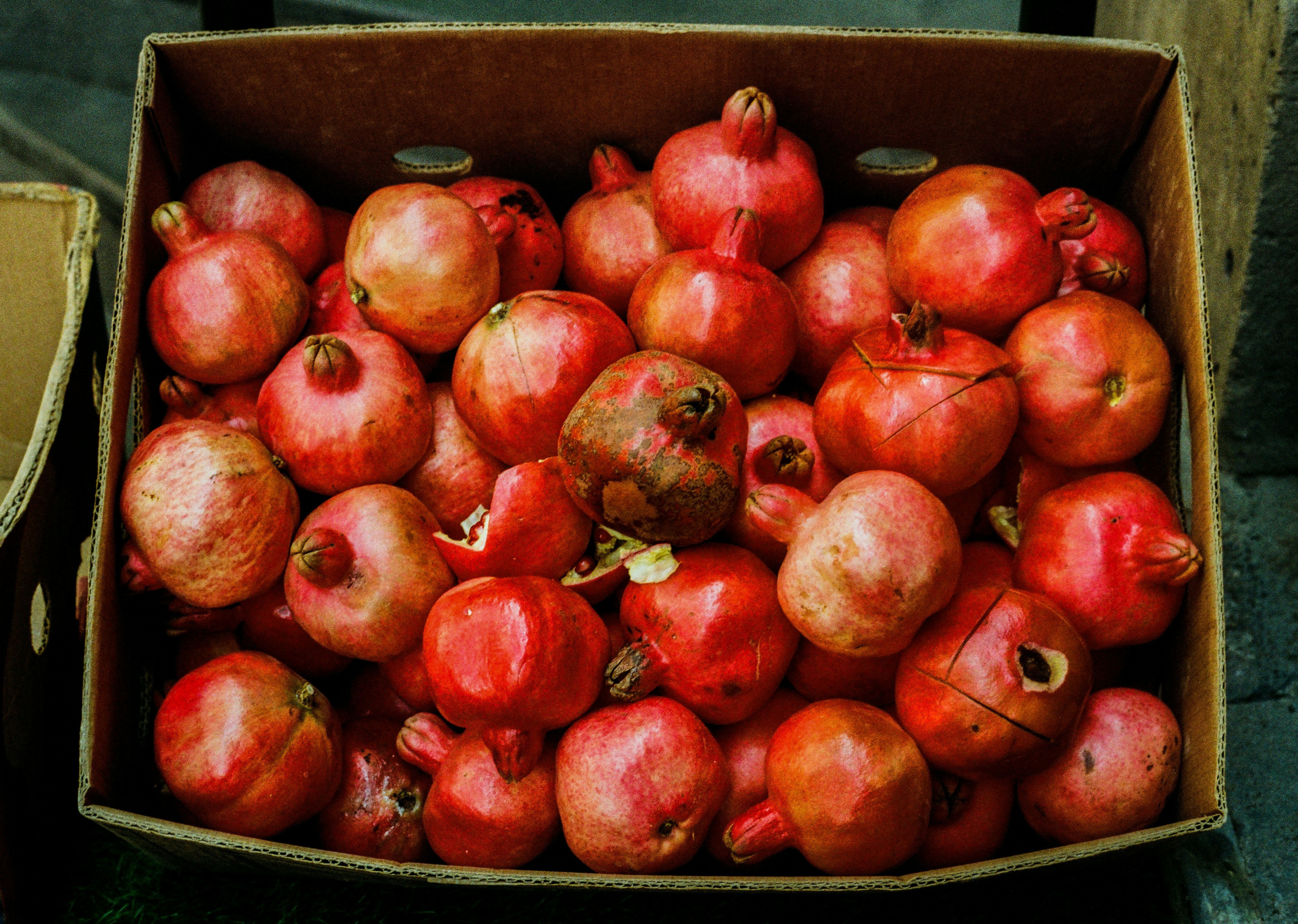 A box full of pomegranates sitting on the ground photo – Free Fruit ...