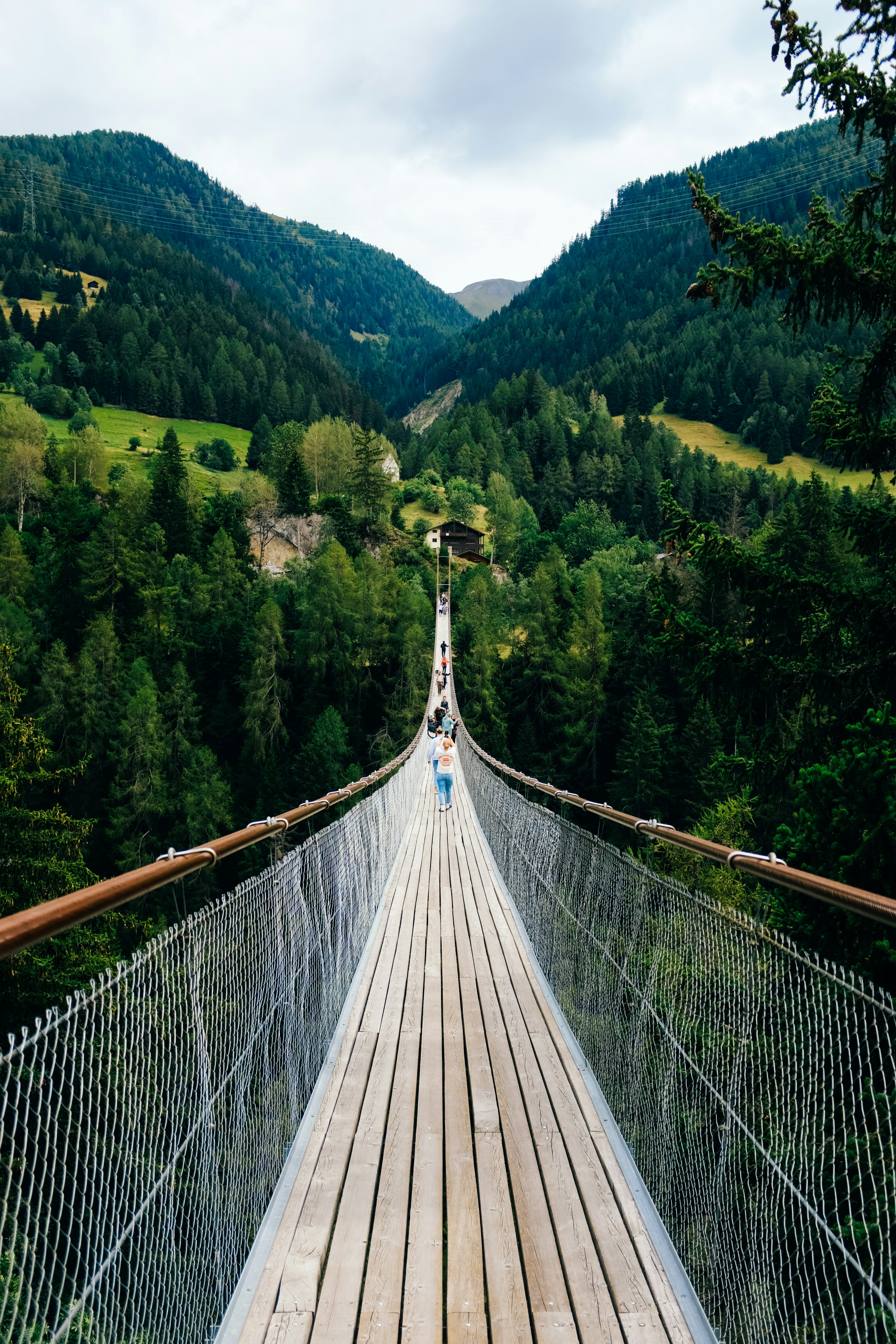 A person walking across a suspension bridge over a river photo – Free ...