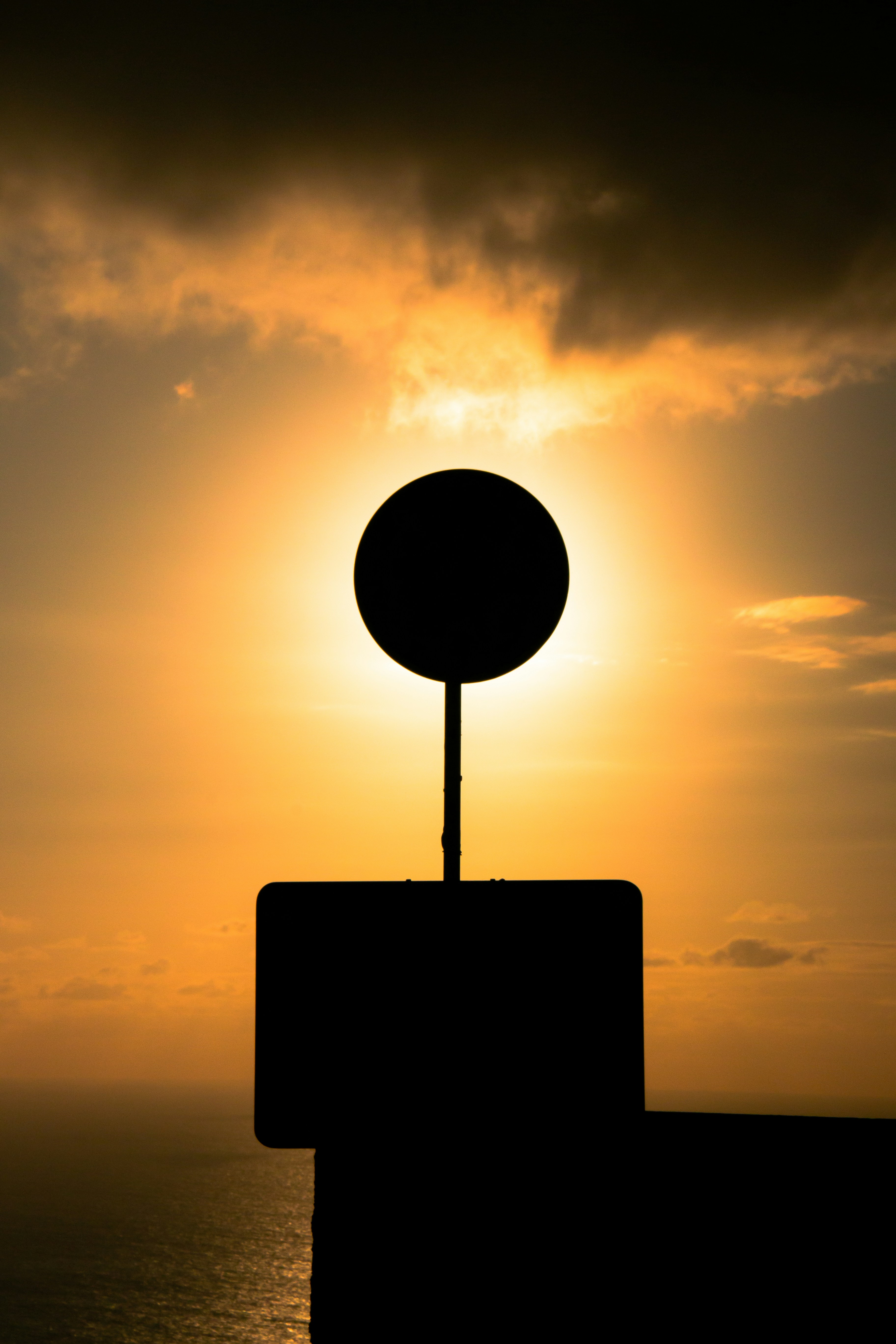 Silhouette at Dusk: A Sunlit Signpost with Circular Top