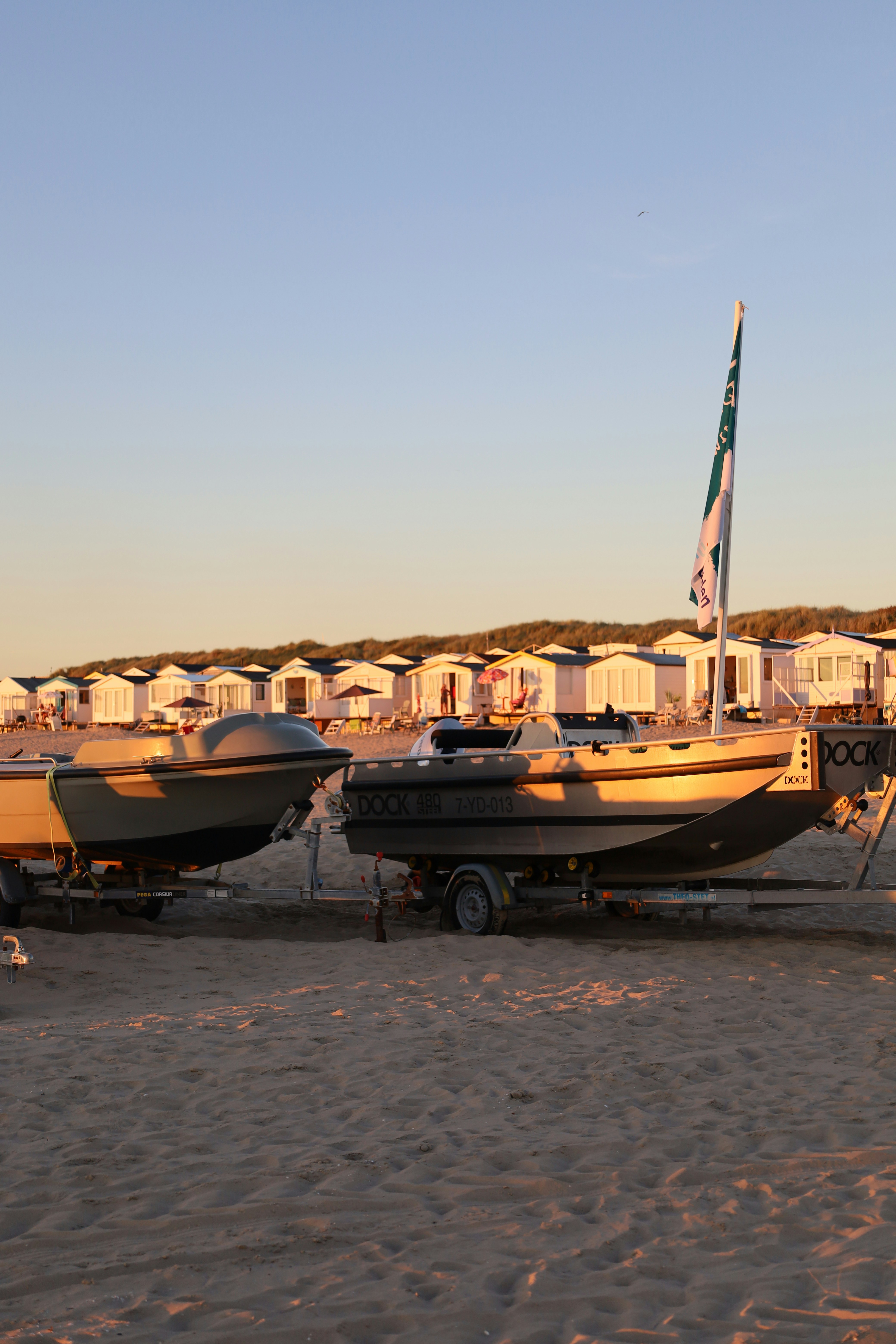Golden Hour Hulls: Boats on Trailers with a Row of Beach Cabins