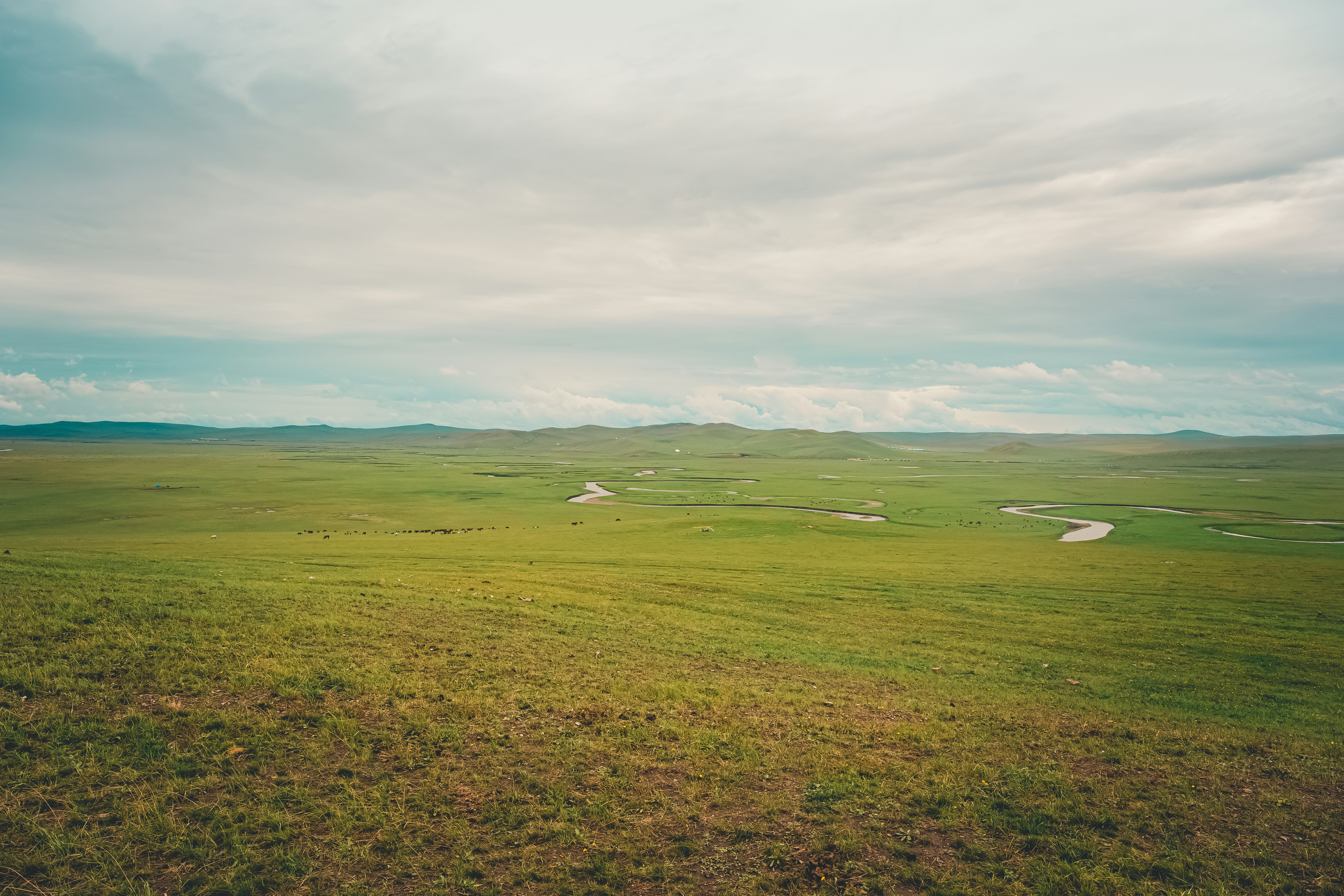 A wide open field with a river running through it photo – Free ...