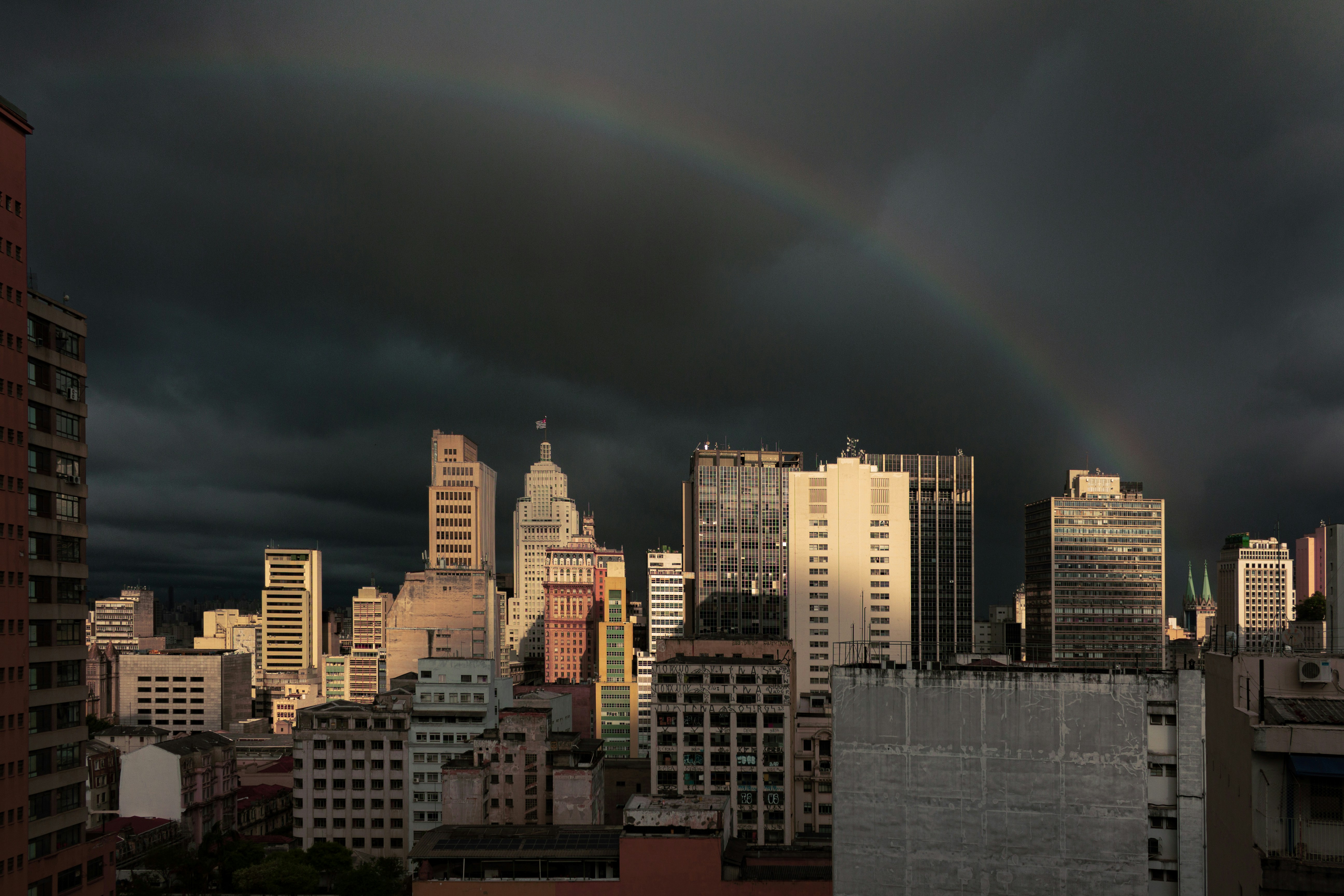 Rainbow Arc over a Moody City Skyline at Dusk