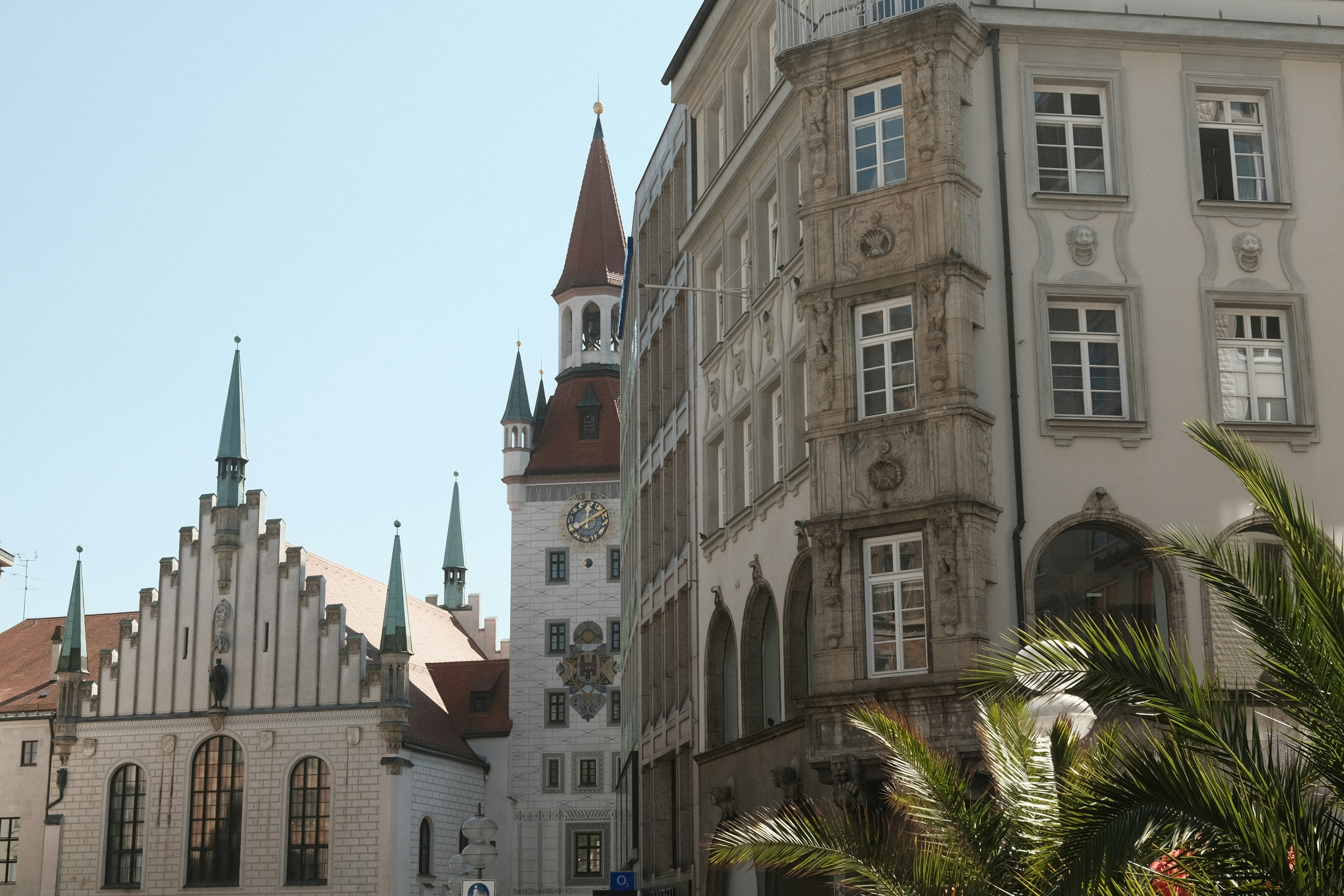 Clock Tower Vista: Sunlit Facades and Palm Fronds Over a European Street