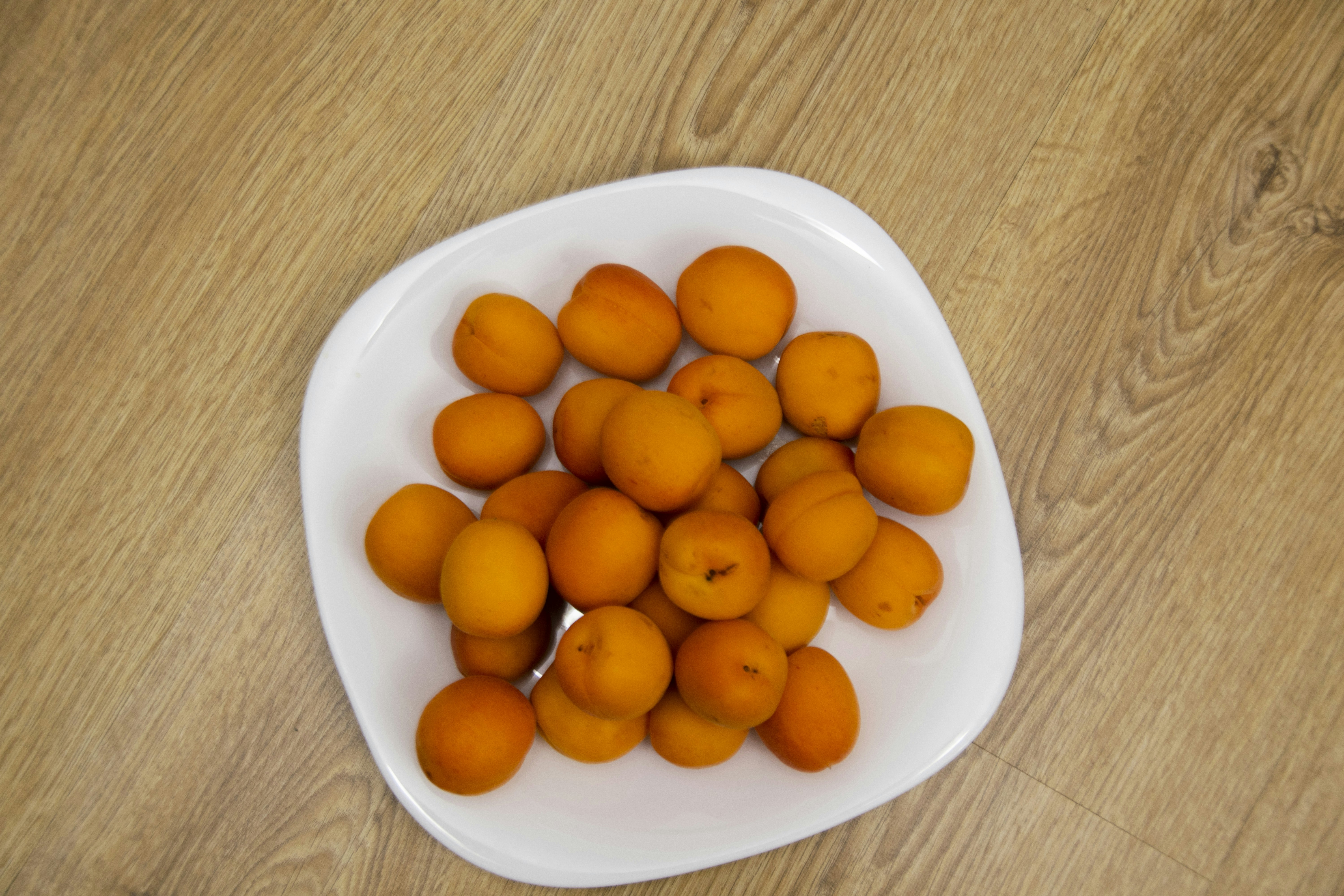 Un cuenco blanco lleno de naranjas encima de una mesa de madera foto ...