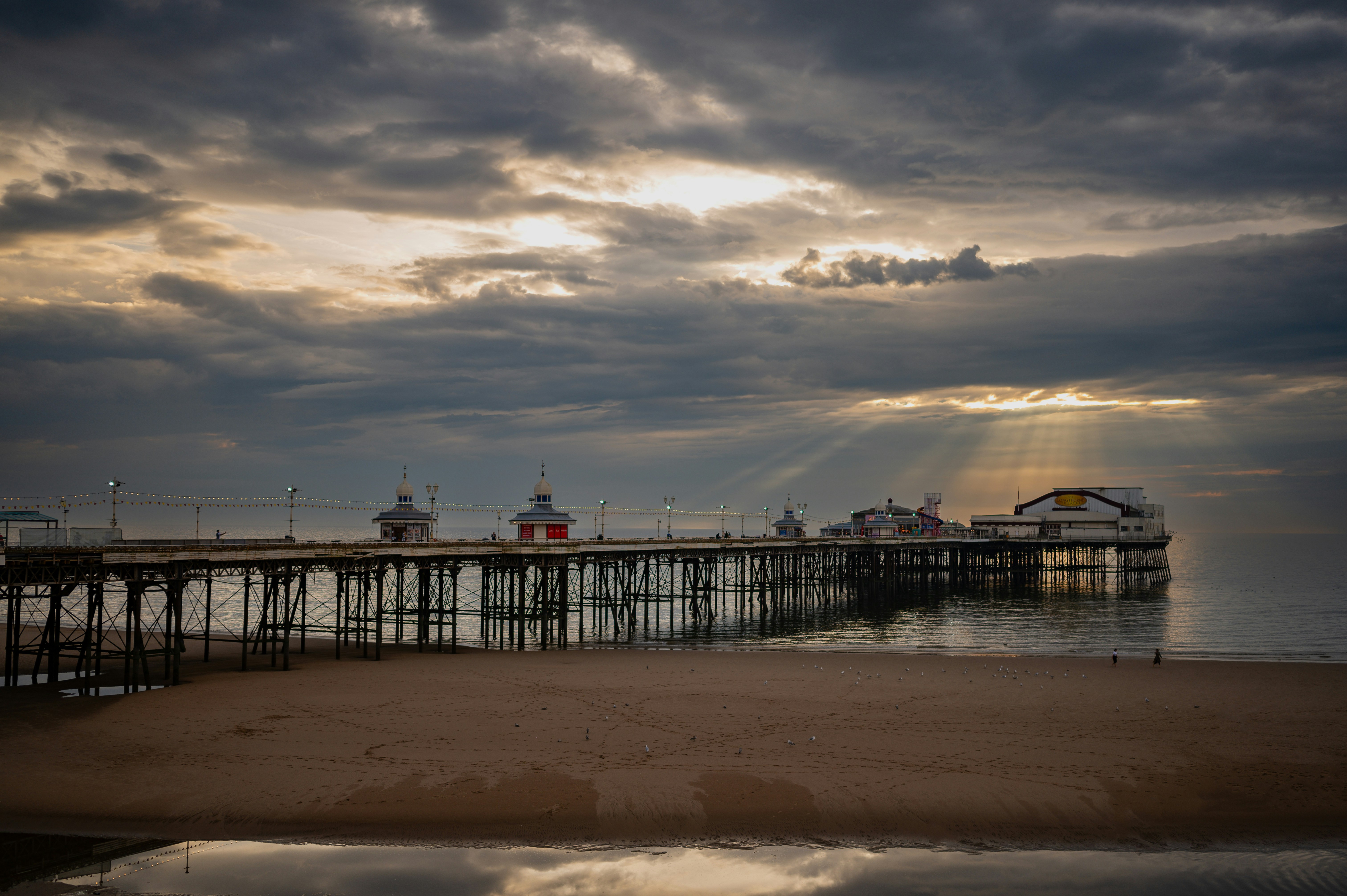 The sun is shining through the clouds over a pier photo – Free Sunset ...