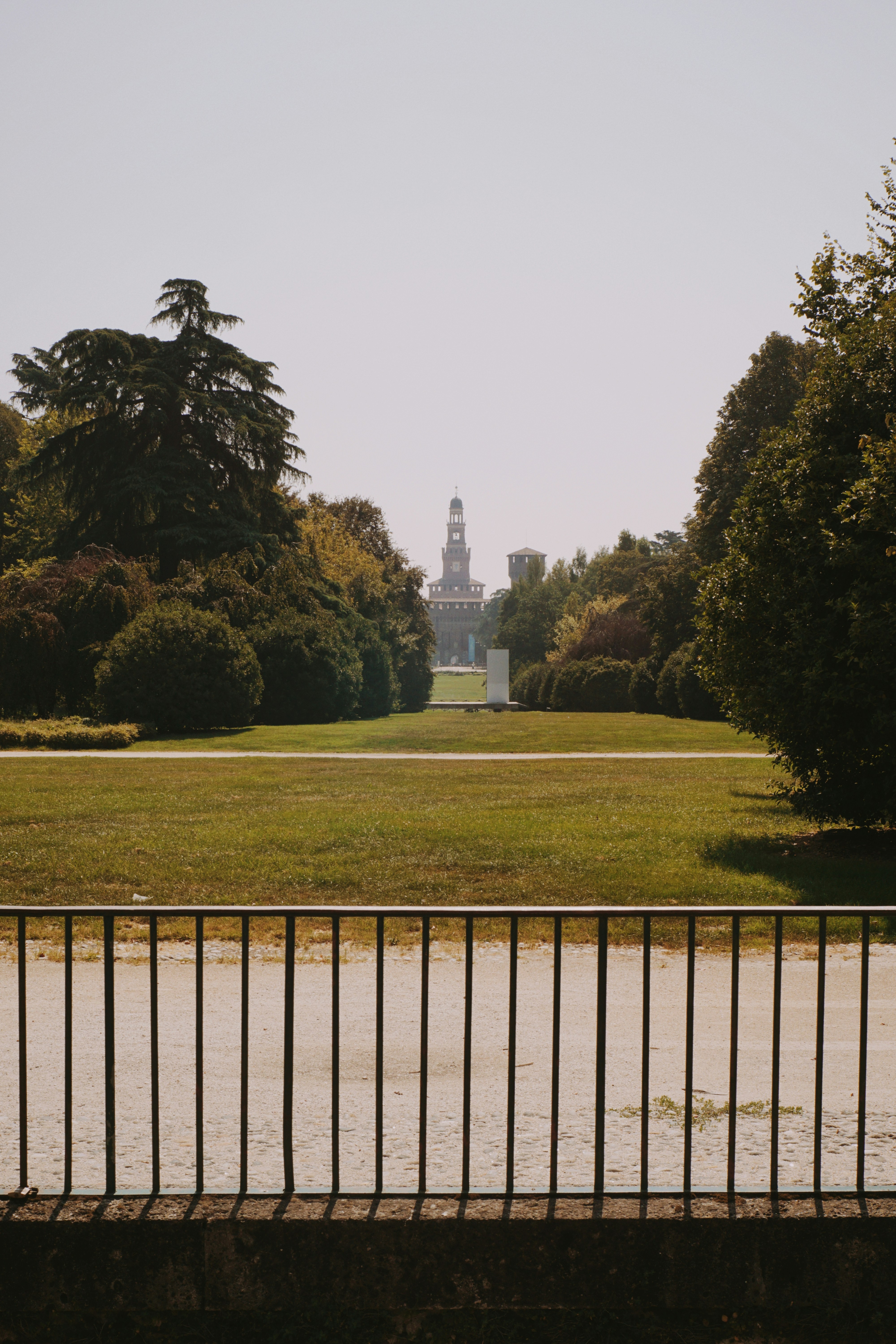 Line of trees and distant monument framed by a fence