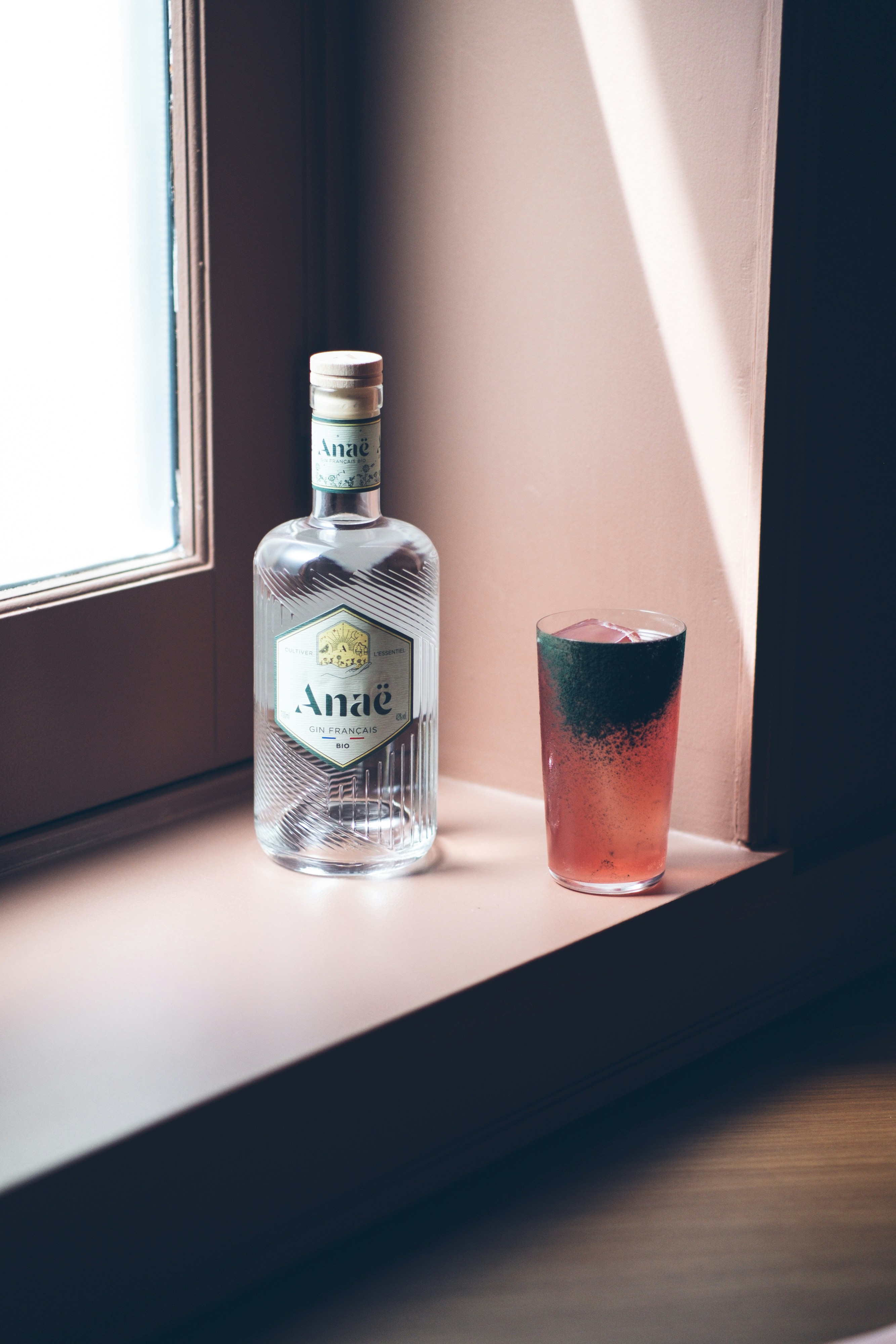 Anaé by the Window: A Quiet Light Moment with Bottle and Glass