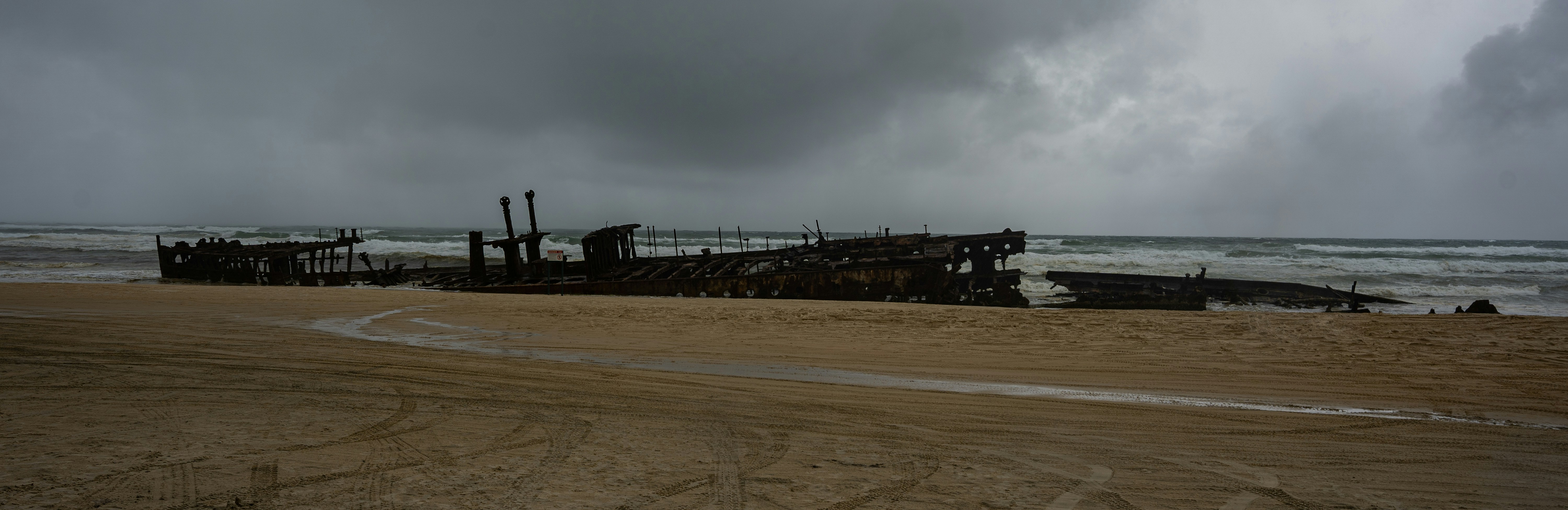 Remnant Pier on a Gray Shore under a Looming Sky