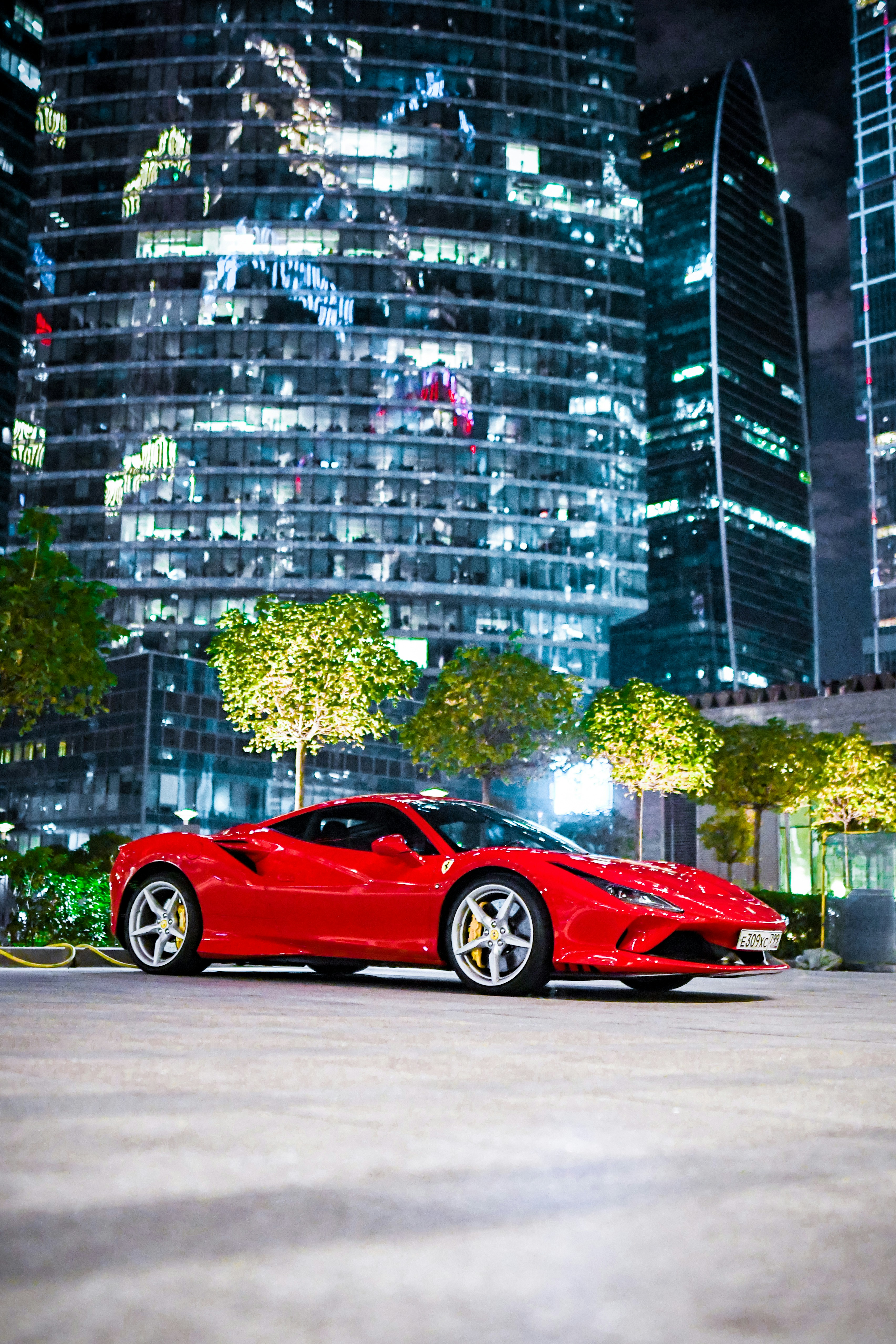 Crimson Exemplar: Red Supercar Beneath Neon Skyscrapers at Night