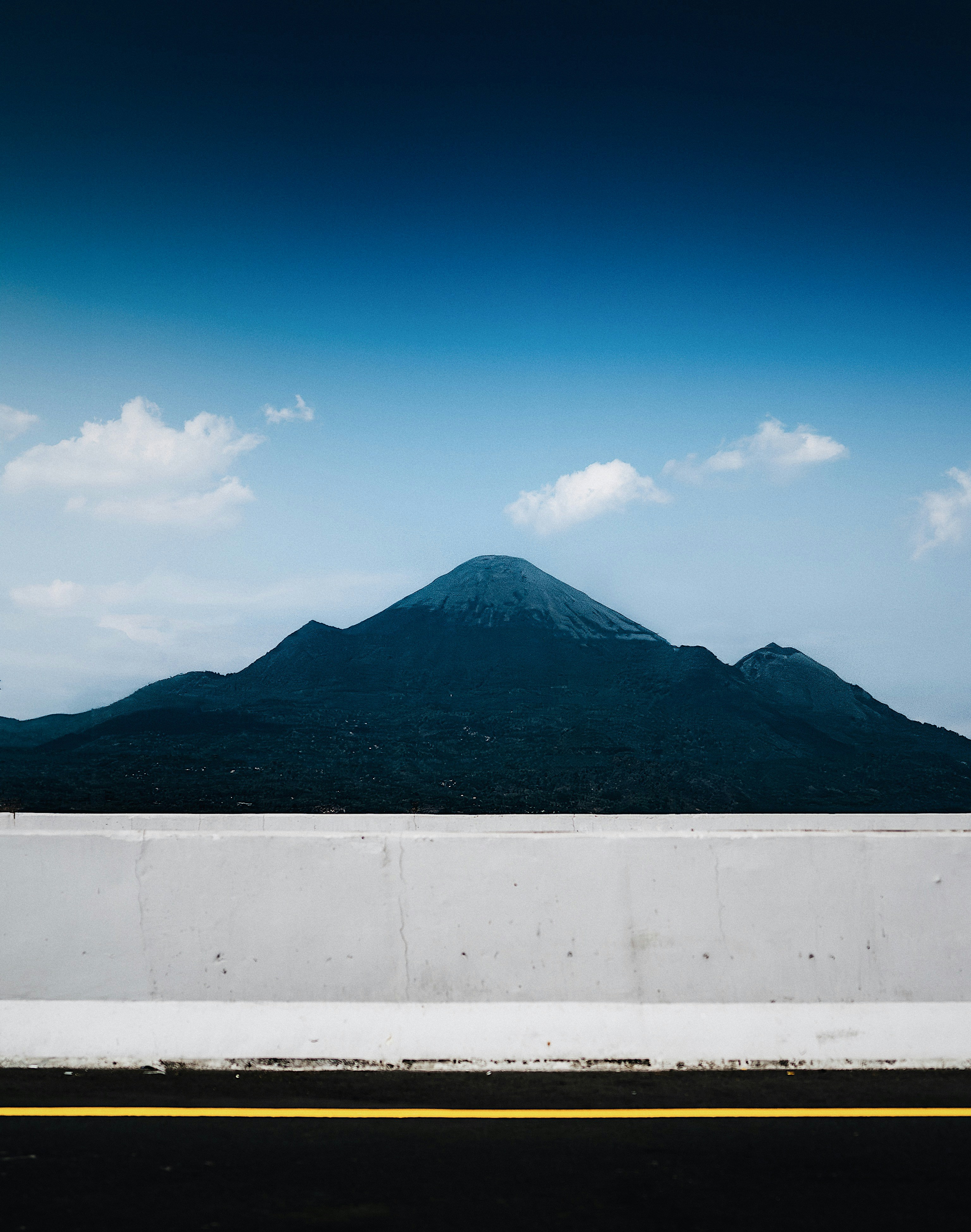Distant Peak Behind a Concrete Barrier Under a Gradient Sky