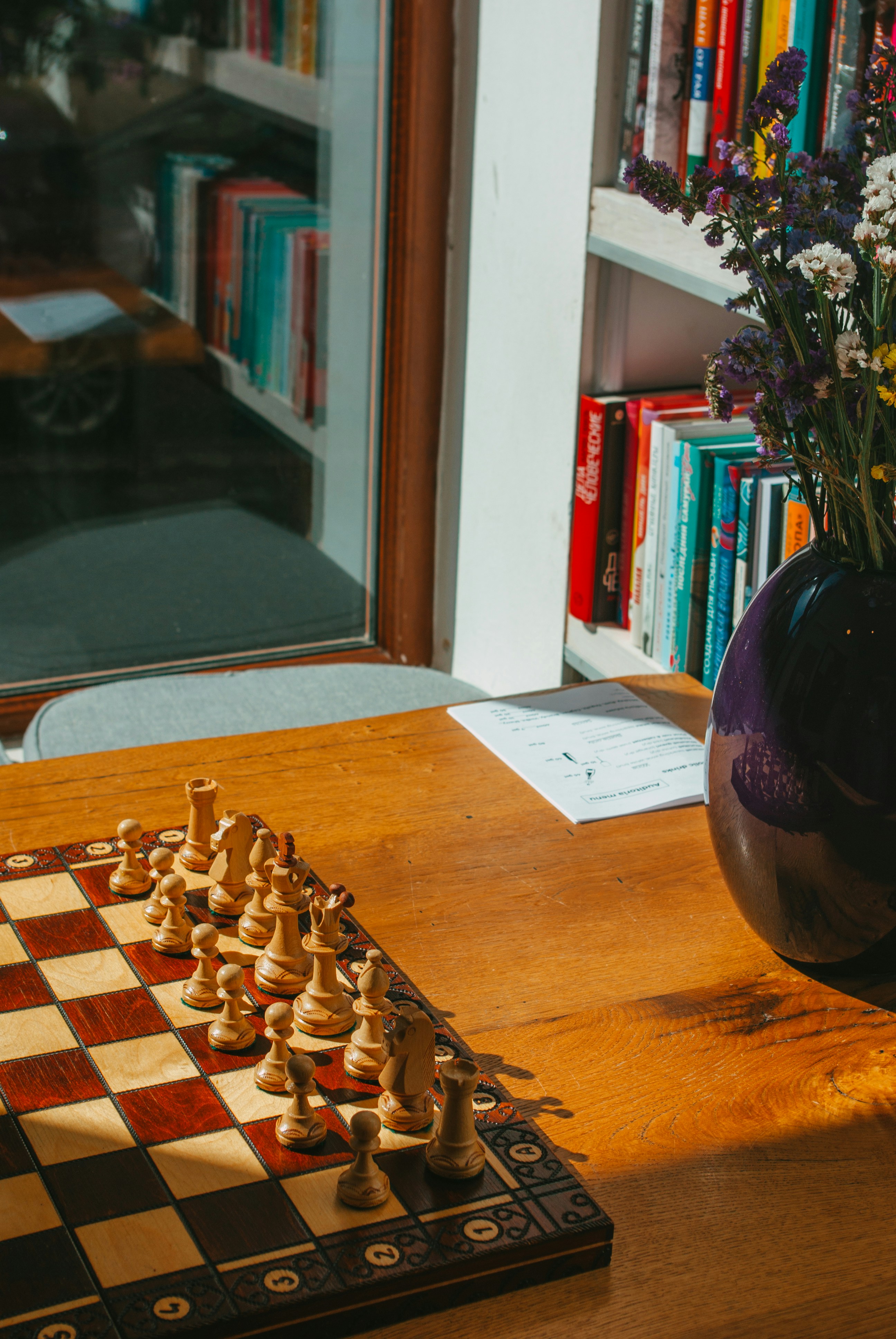 Sunlit Gambit by the Window: Chessboard, Flowers, and Books