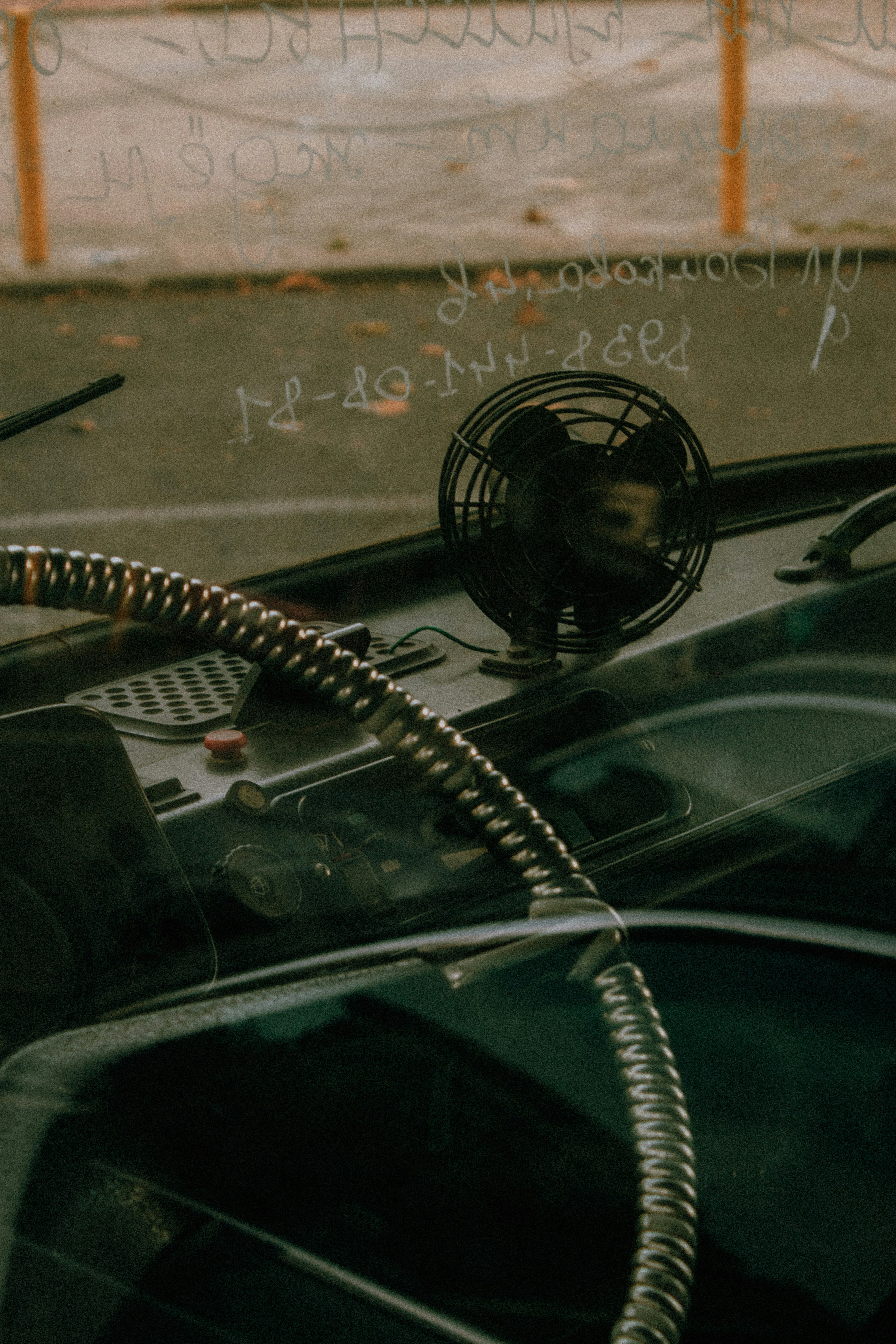 Cockpit Currents: A lone dash fan amid spiraled cables behind a weathered windshield