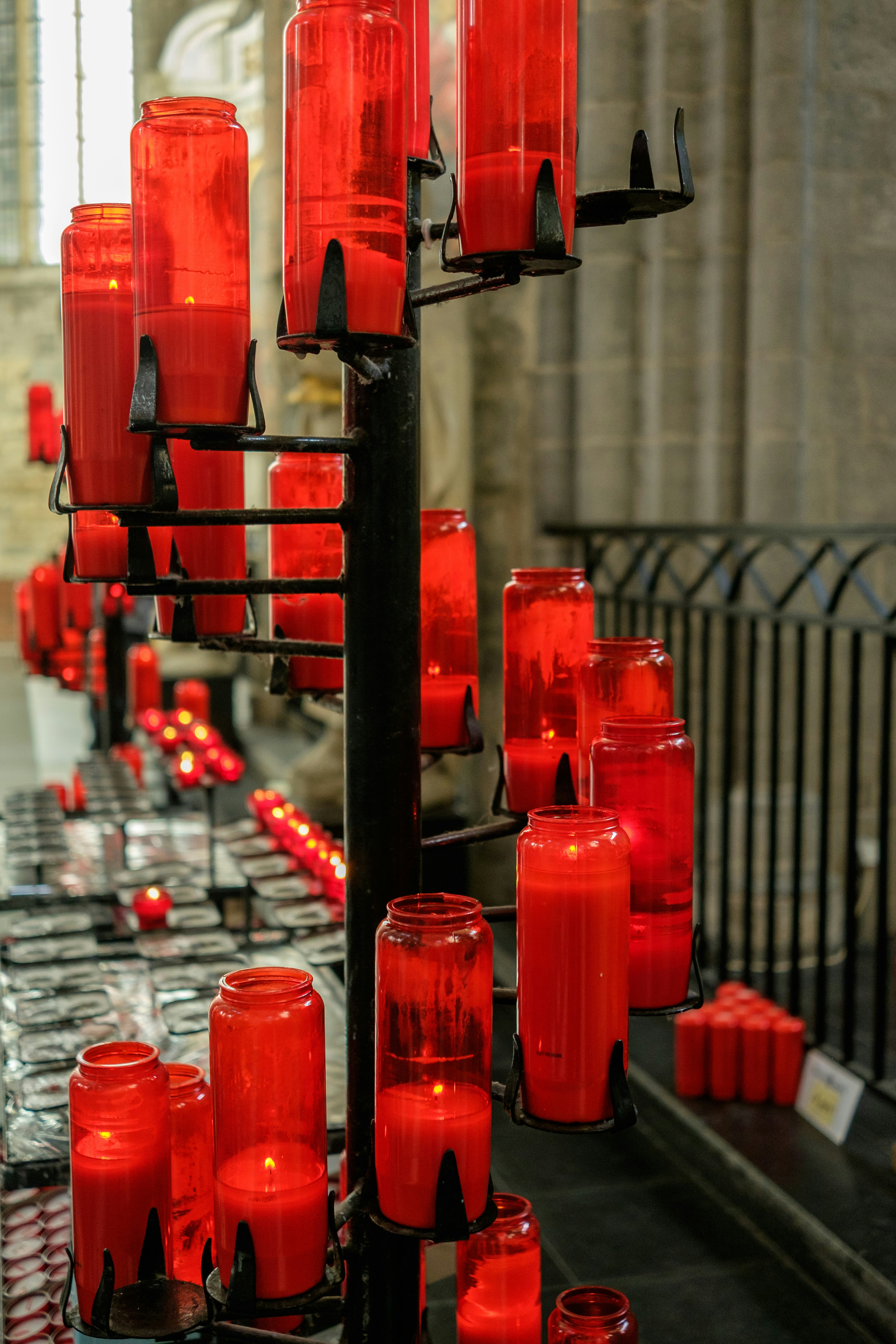 Crimson Votive Cascade Along a Cathedral Rail