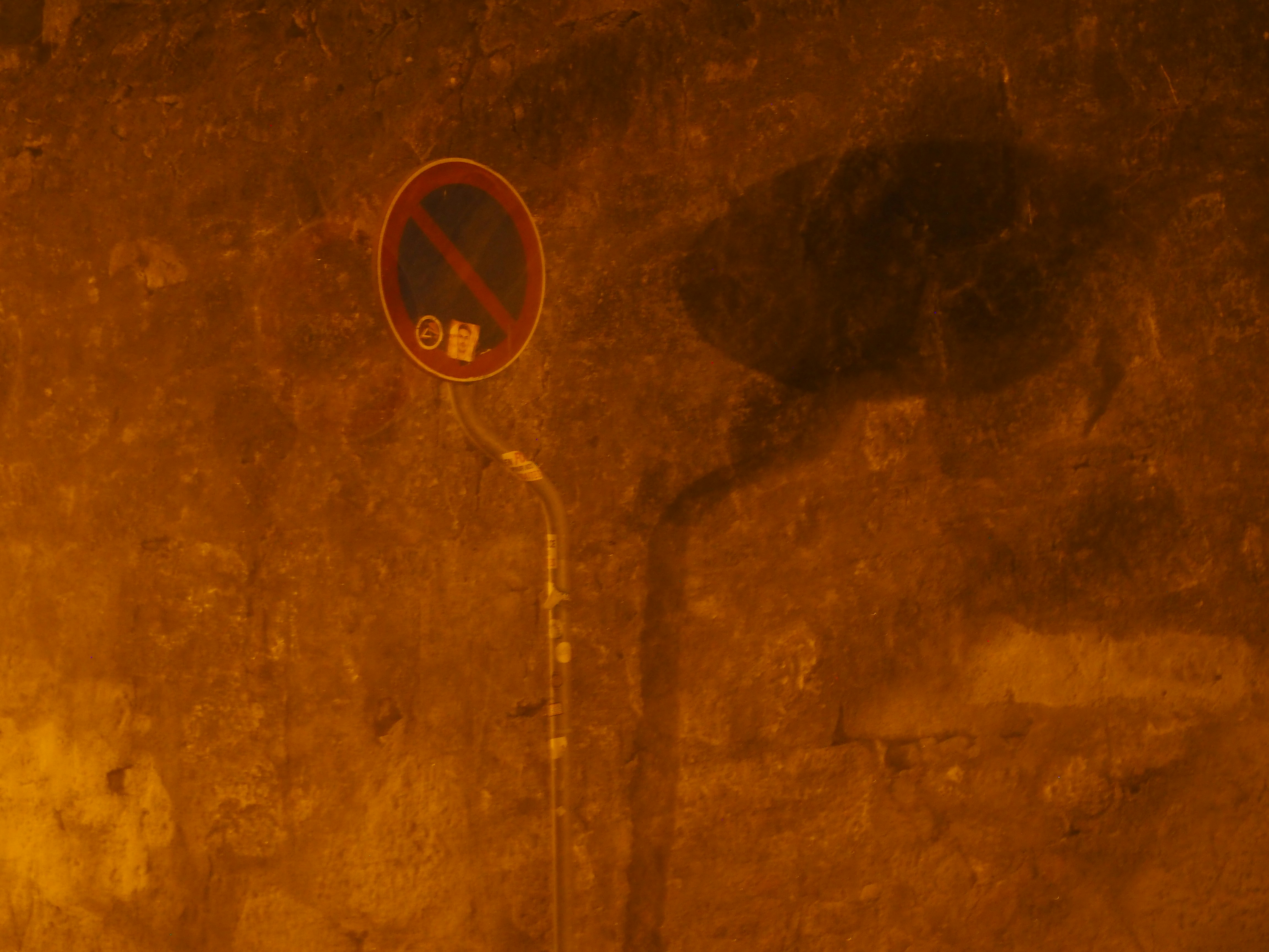 No Parking Sign Anchored to a Weathered Wall, Bathed in Warm Night Light