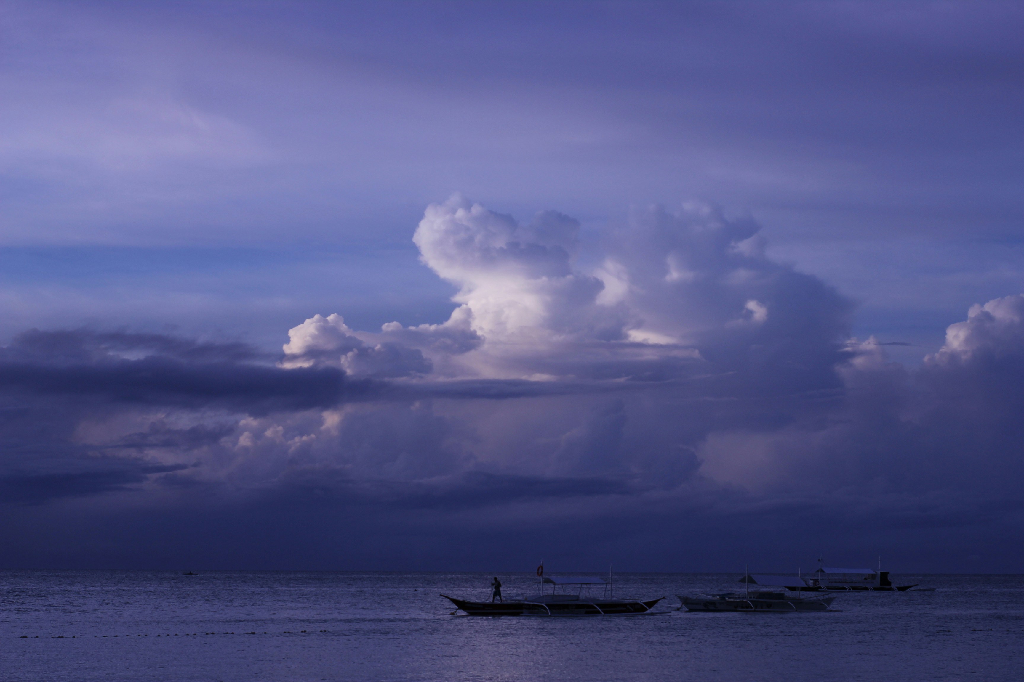 Cobalt Canopy Over a Quiet Sea: Boats Beneath a Towering Cloud