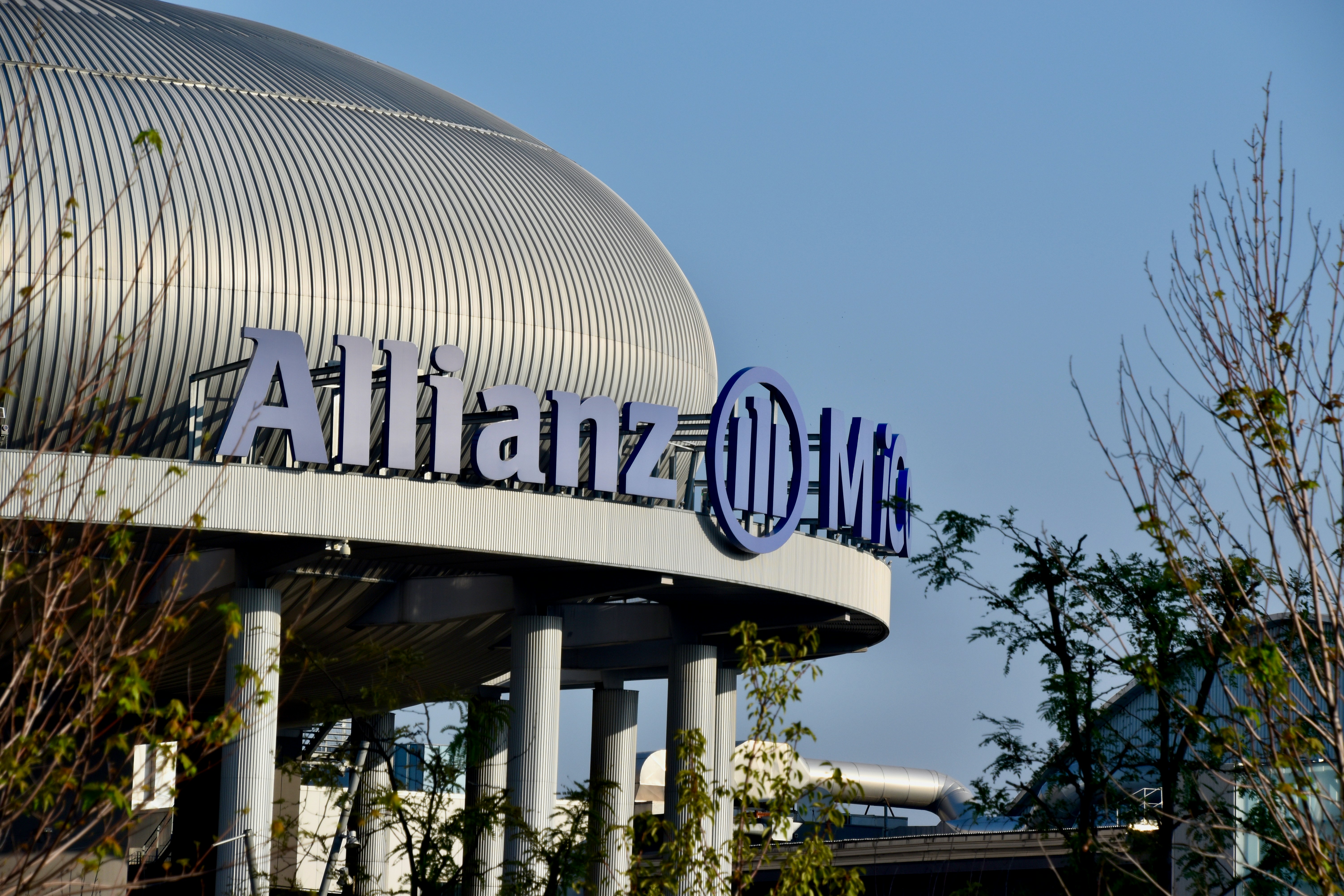 Contemporary building facade with curved metal design and prominent signage against a clear blue sky.