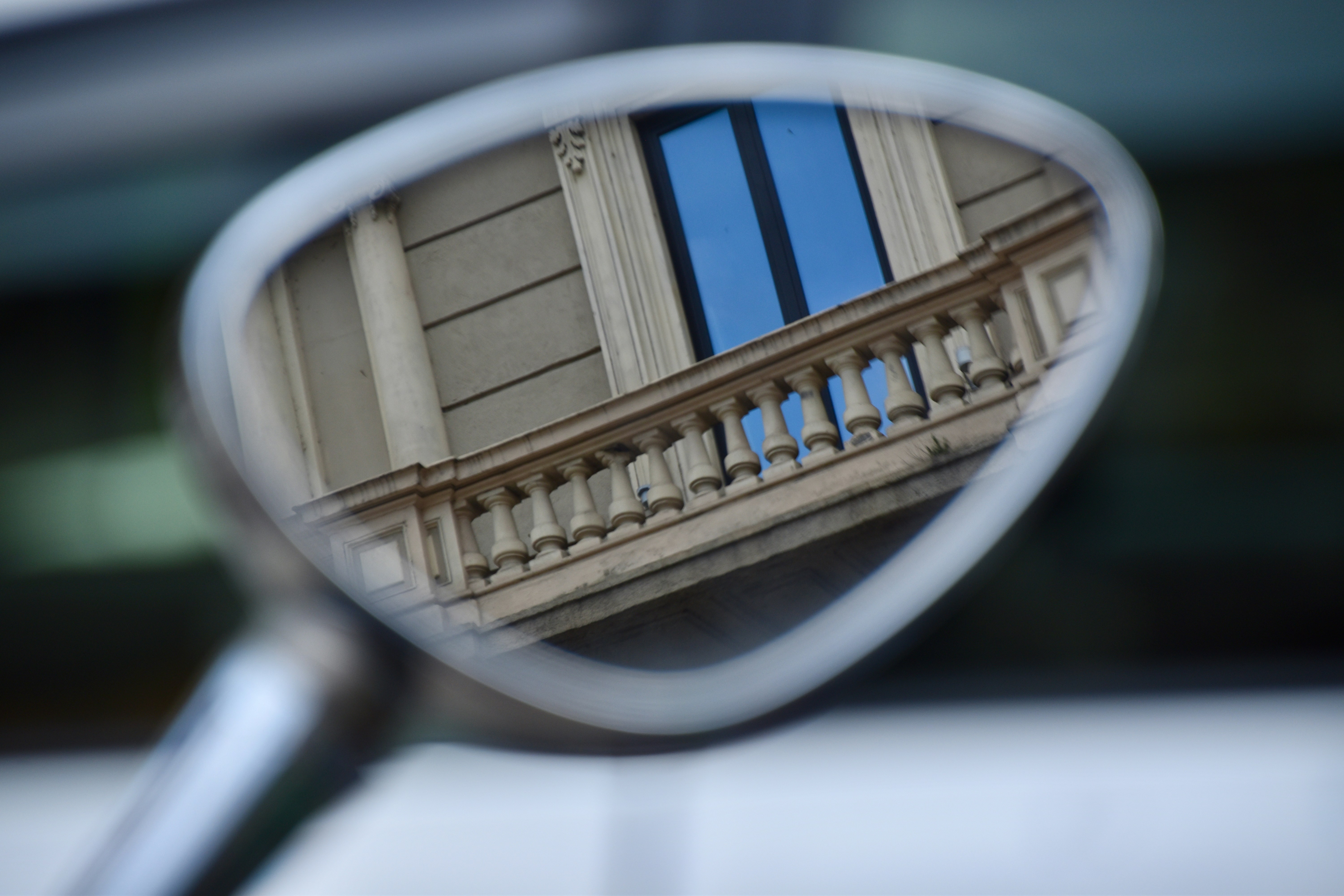 Blue Window Reflected: Balcony Details in a Car Mirror