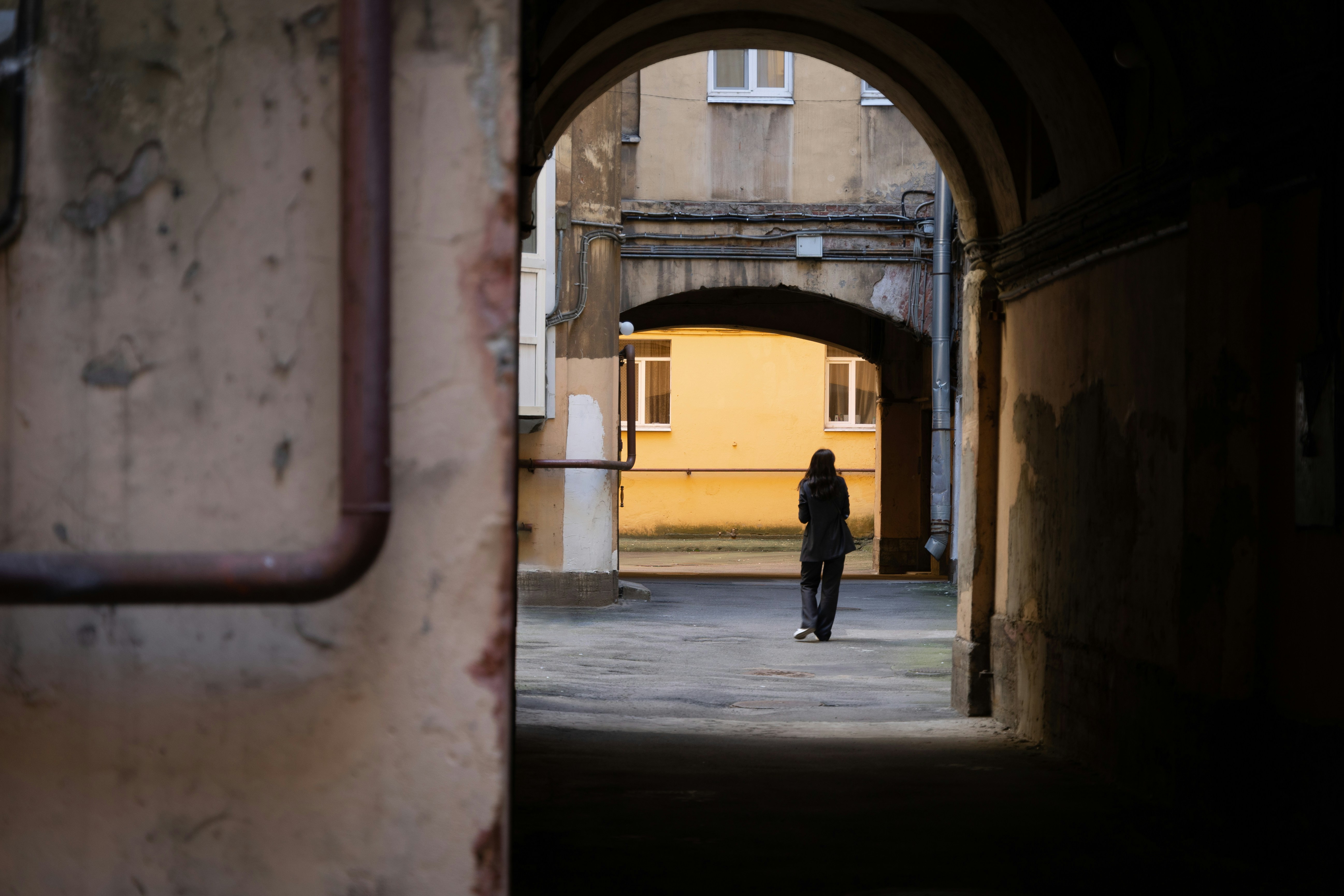 Archway Passage: A lone figure steps from shadow into sunlight