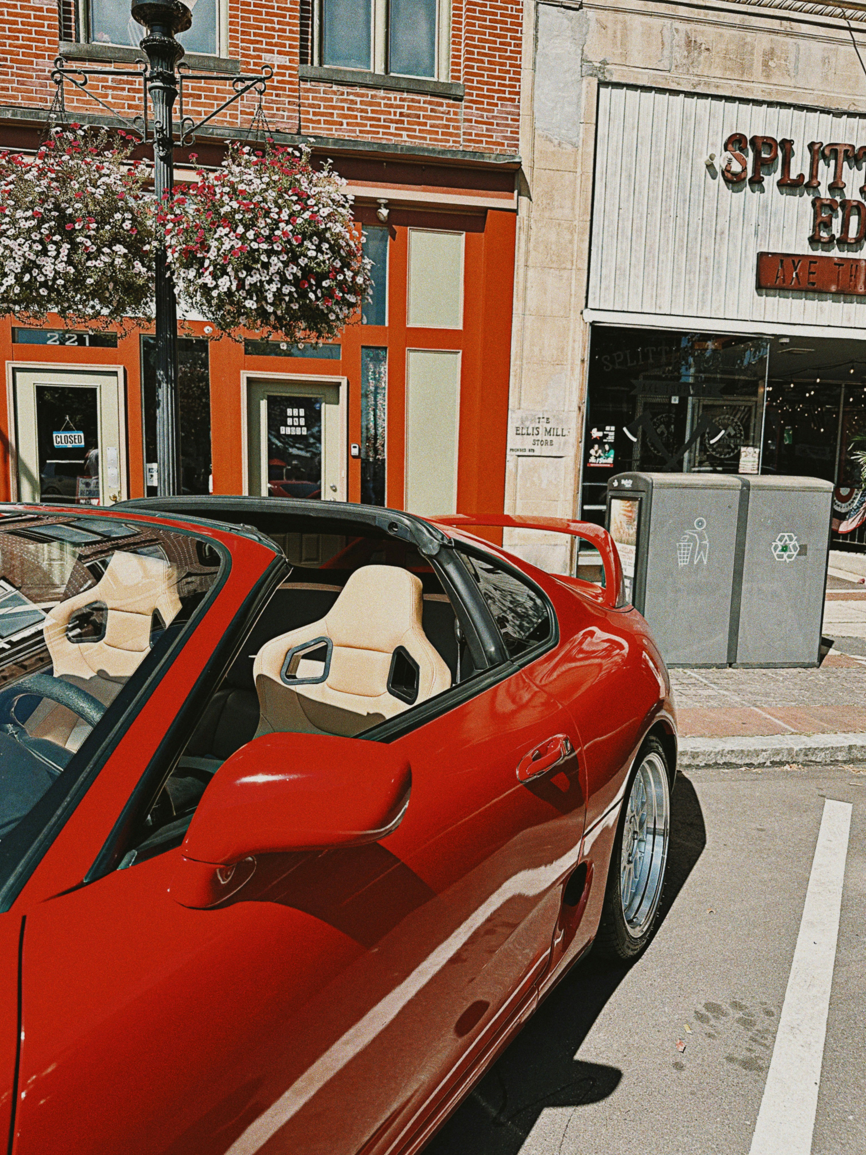 Crimson Roadster Framed by Flowered Facades on a Downtown Street