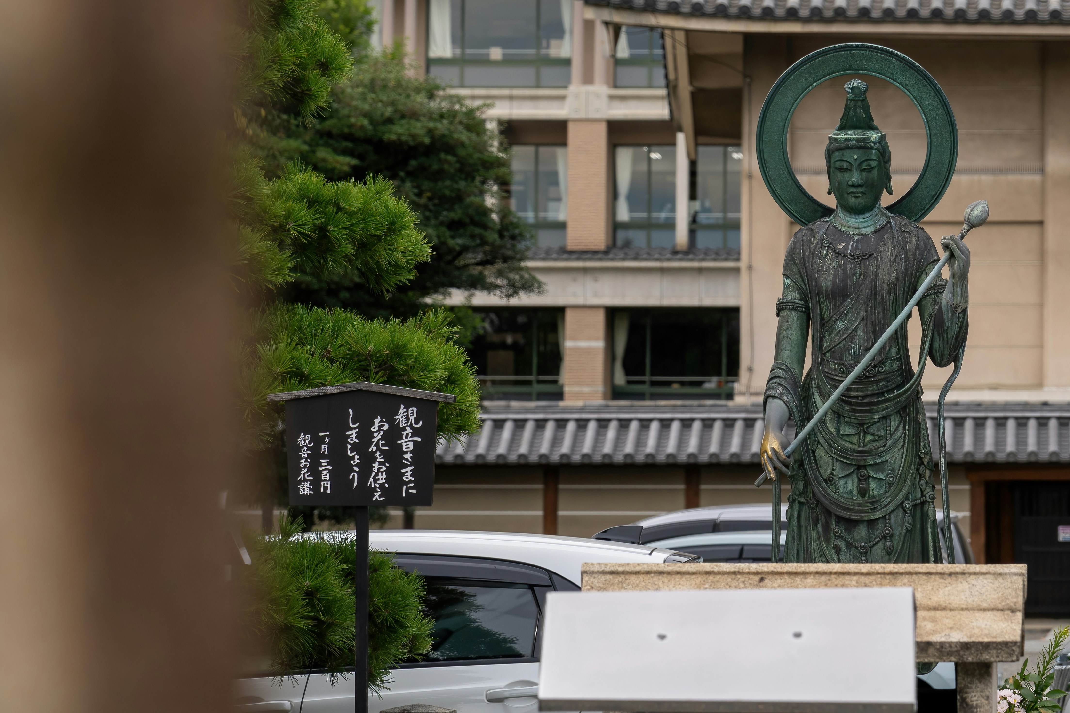 Guardian in Metal: A Buddhist Statue Framed by Urban Architecture