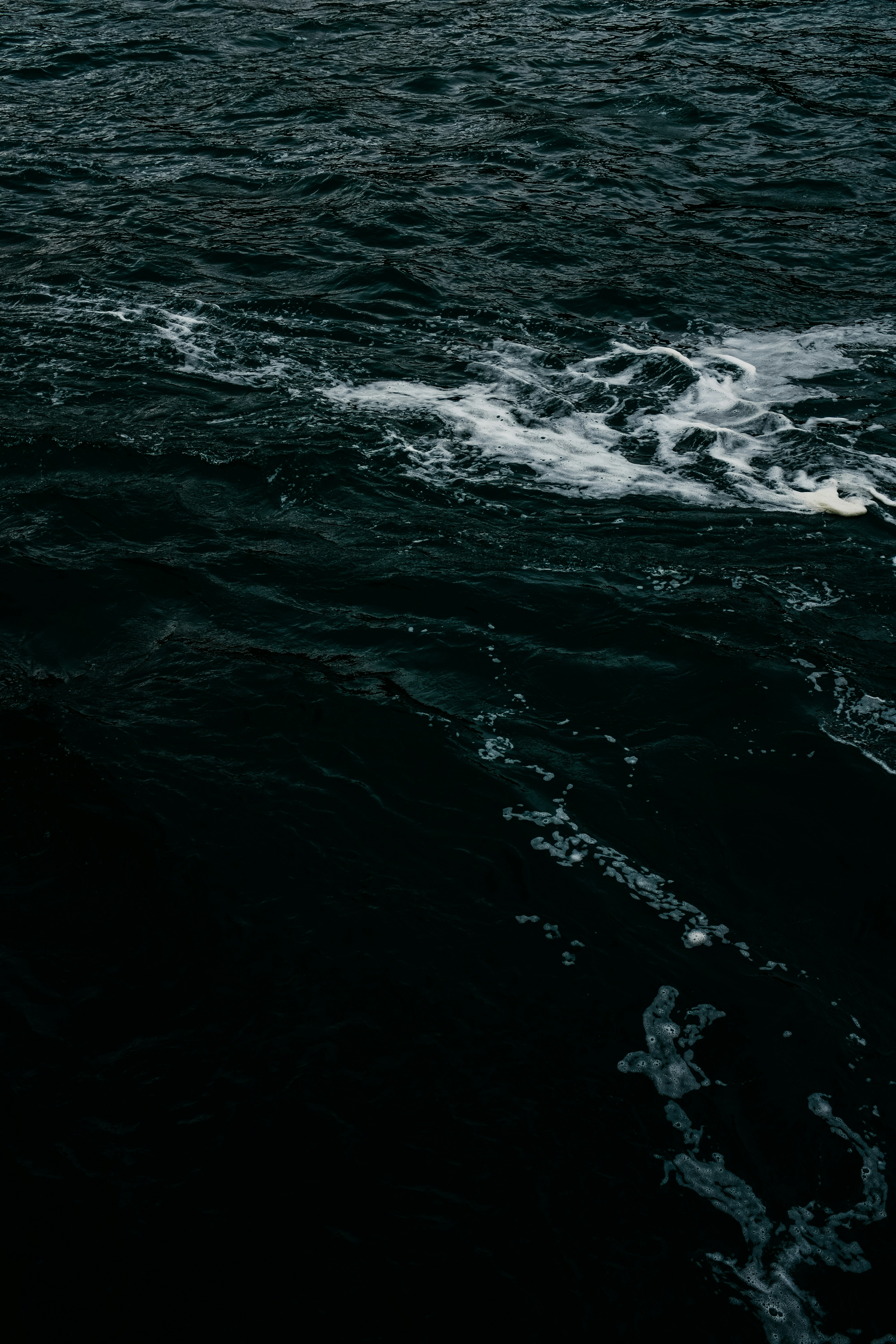 Nocturnal Wake: A Narrow Foam Trail Across a Dark Ocean Surface