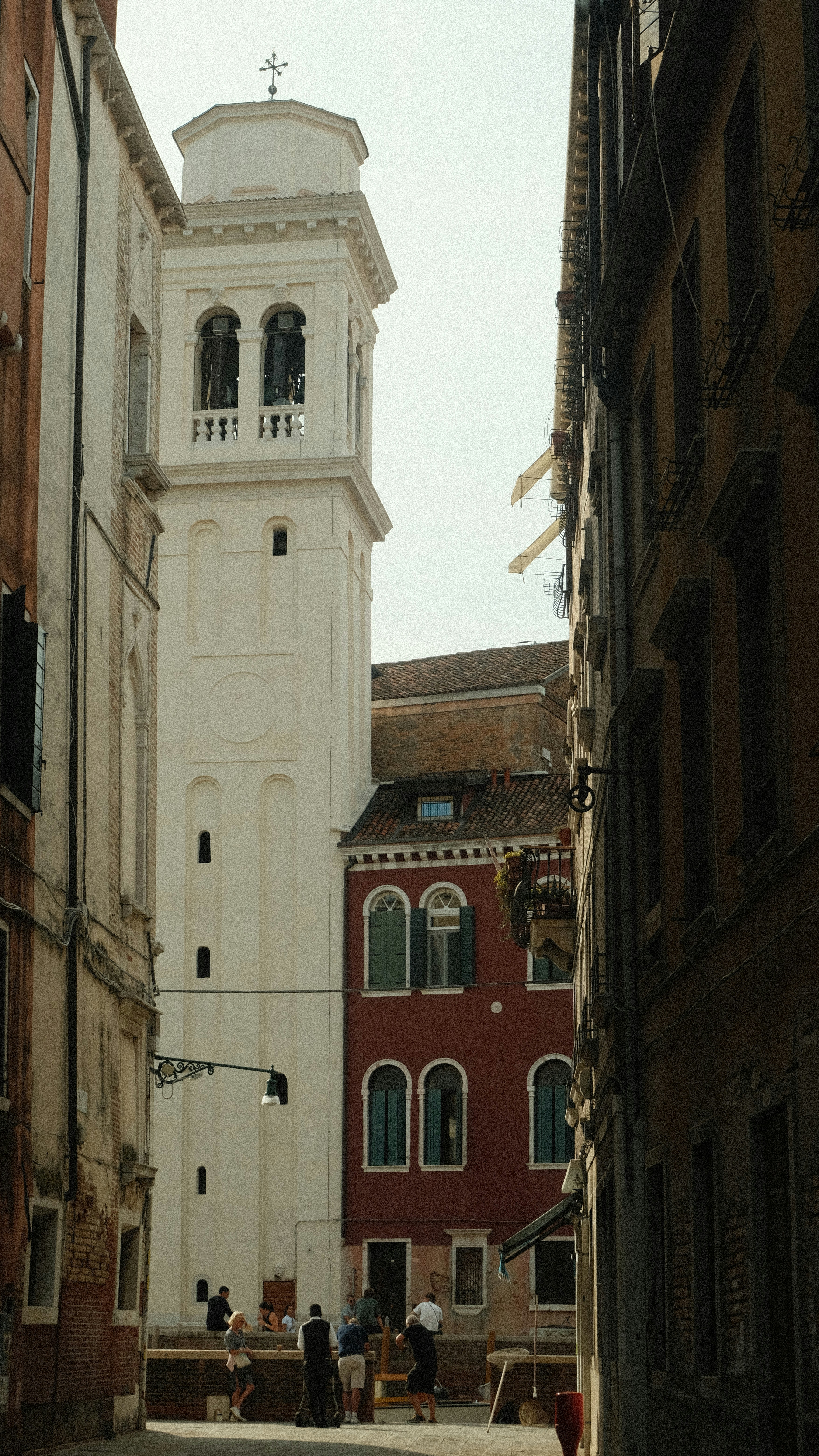 White Bell Tower Rising Between Narrow Historic Facades