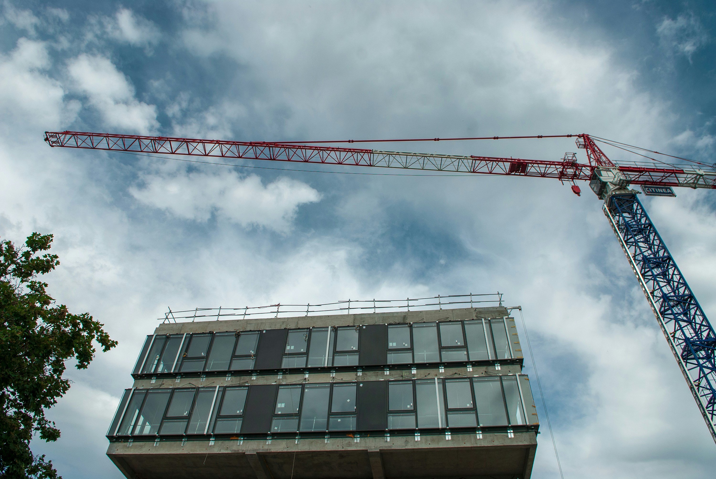 Crane Span Over a Glass-Box Facade Against a Cloudy Sky
