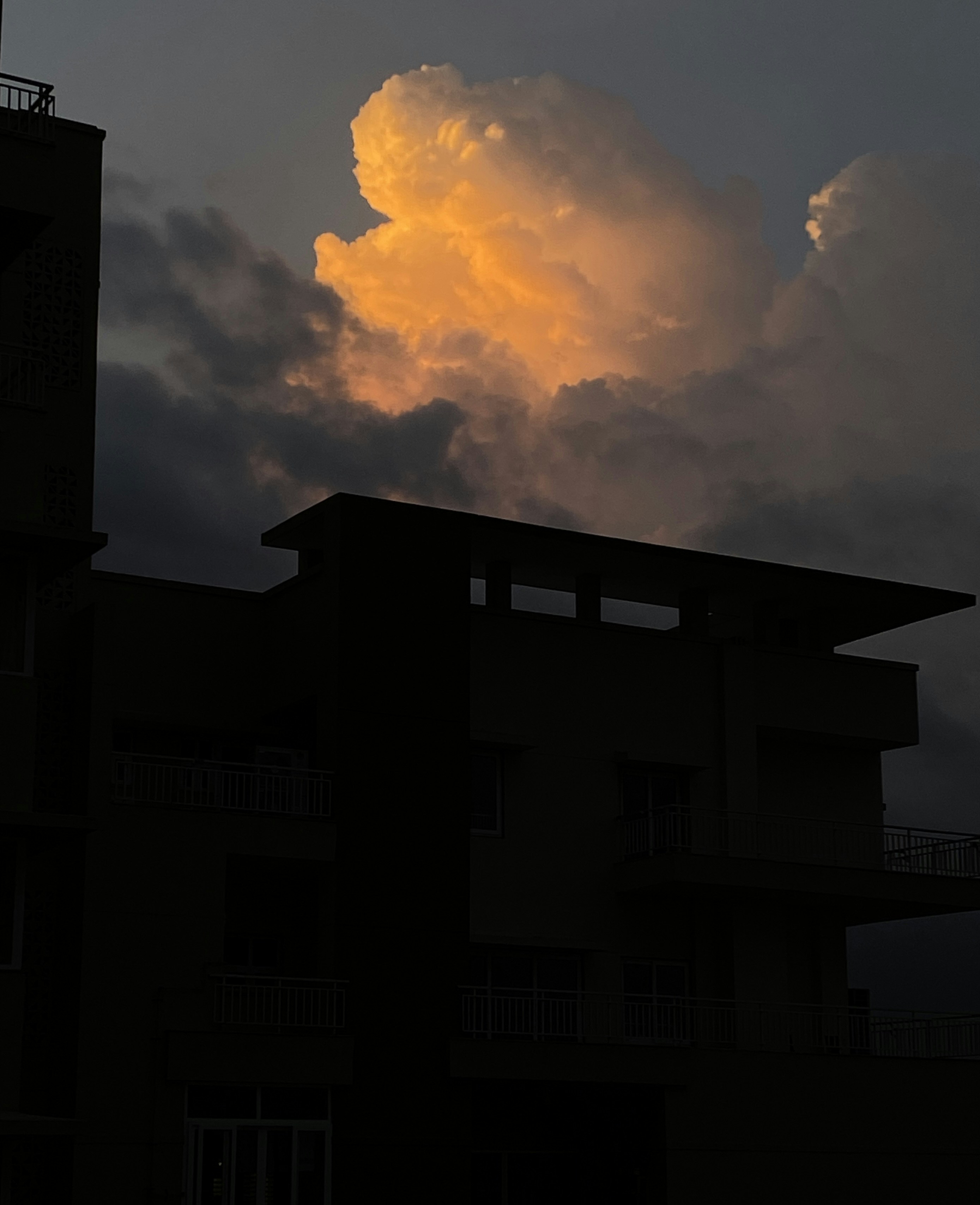 A large cloud looms over a building with balconies photo – Free ...