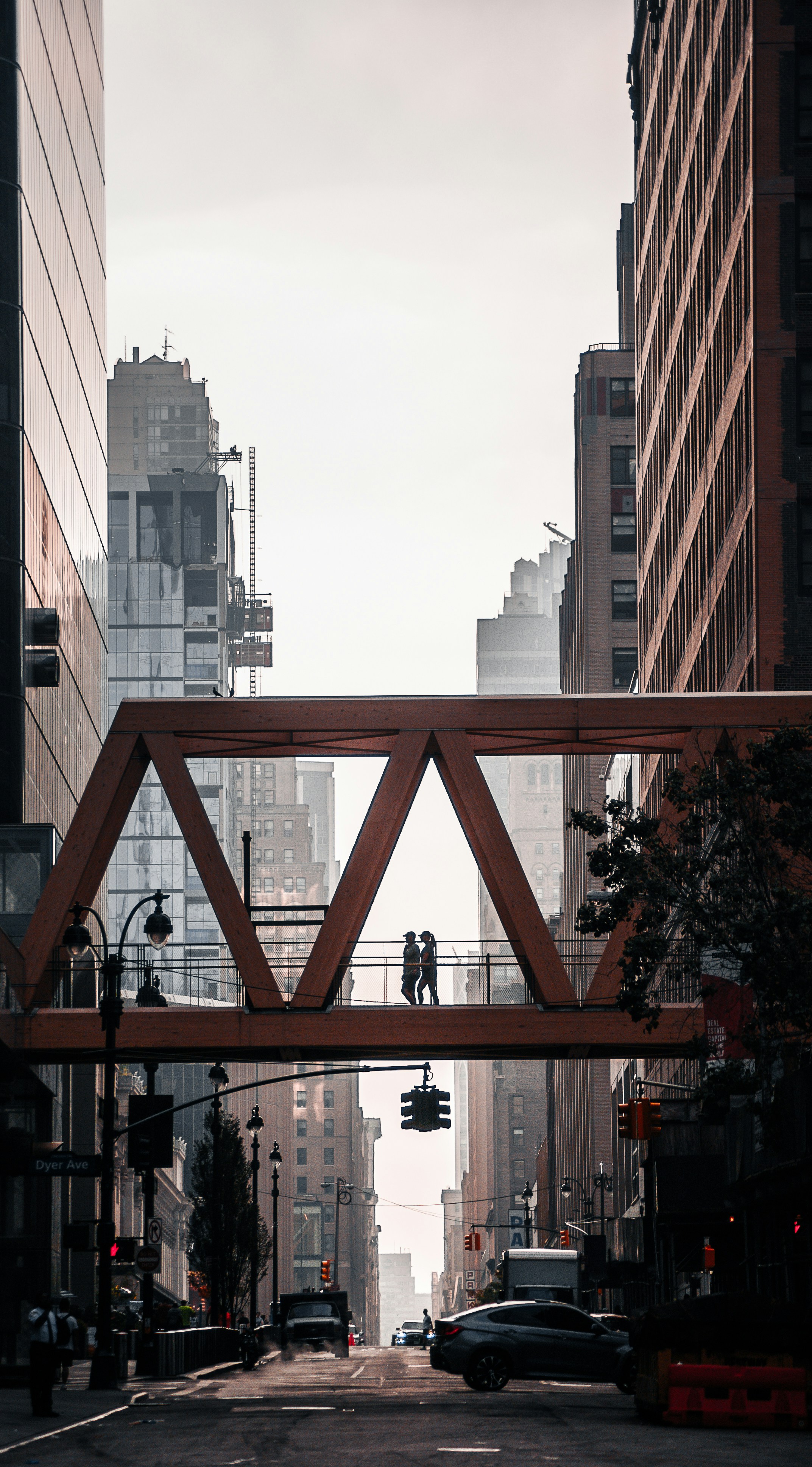 A pedestrian bridge over a city street with tall buildings photo – Free ...