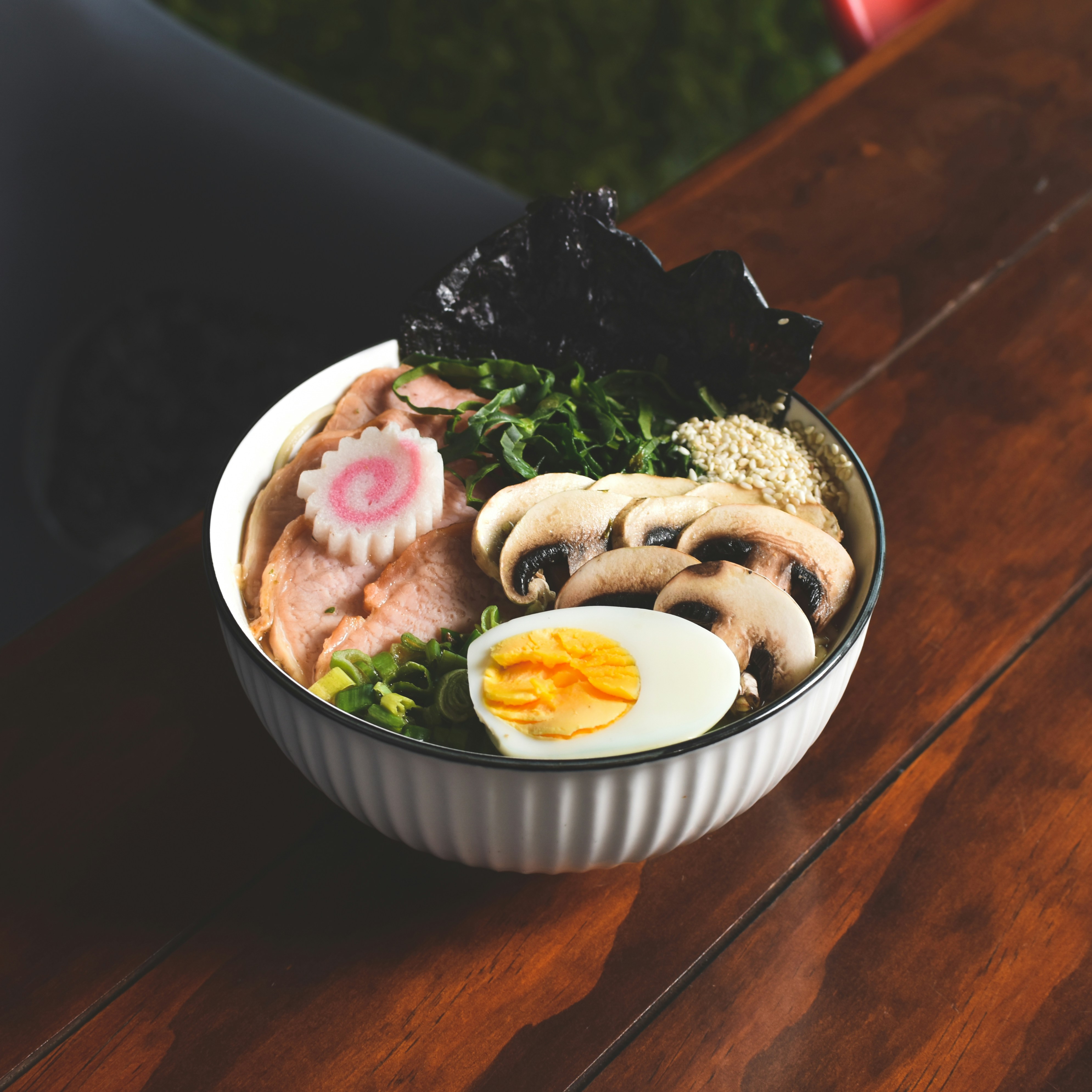 Ramen Ritual on Wood: A glossy bowl brimming with egg, narutomaki, pork, greens, and seaweed