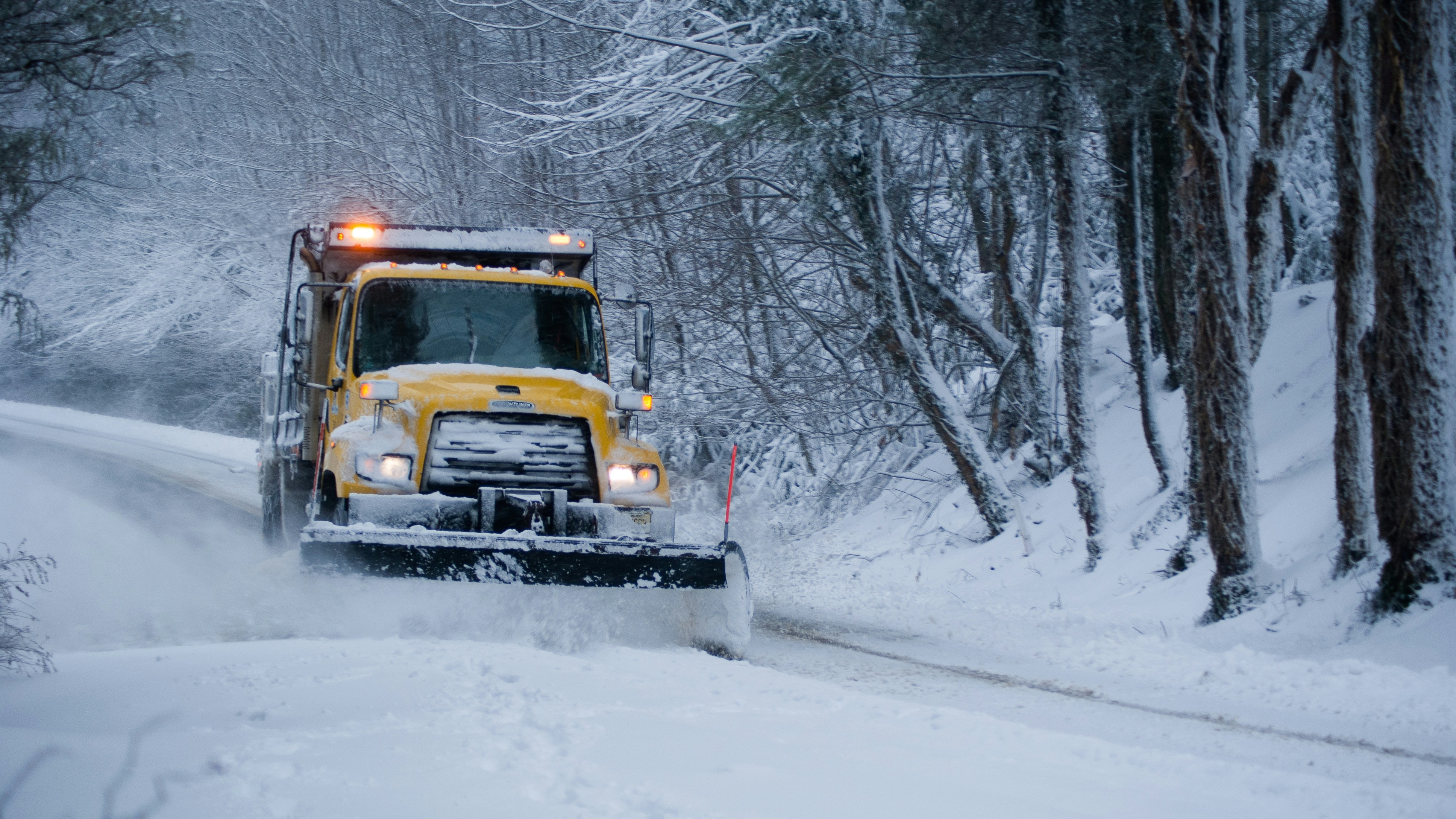 A snow plow driving down a snow covered road photo – Free Snow Image on ...