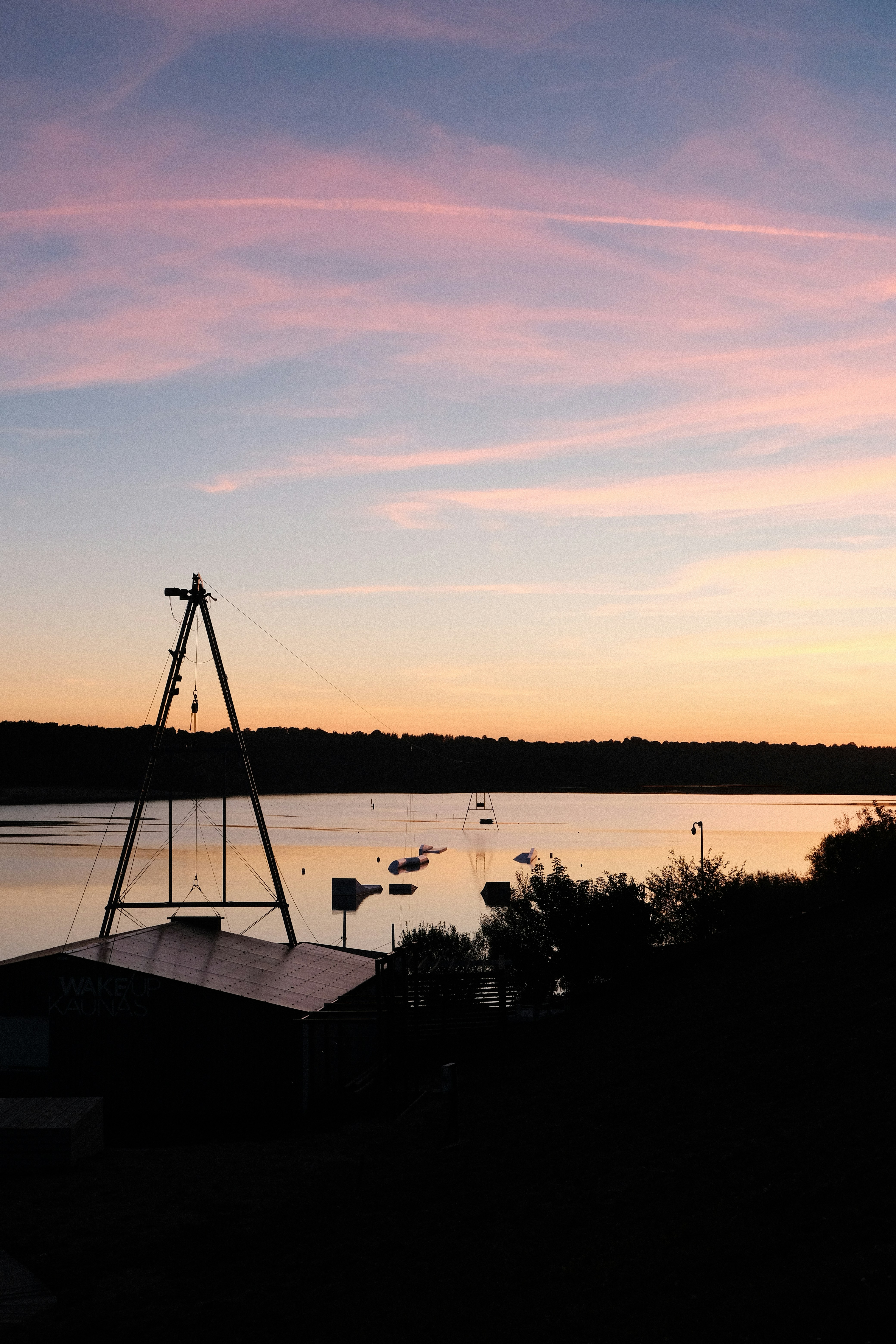 Silhouette by the Shore: A Dusk-Tinted Scene with a Crane against a Calm Horizon