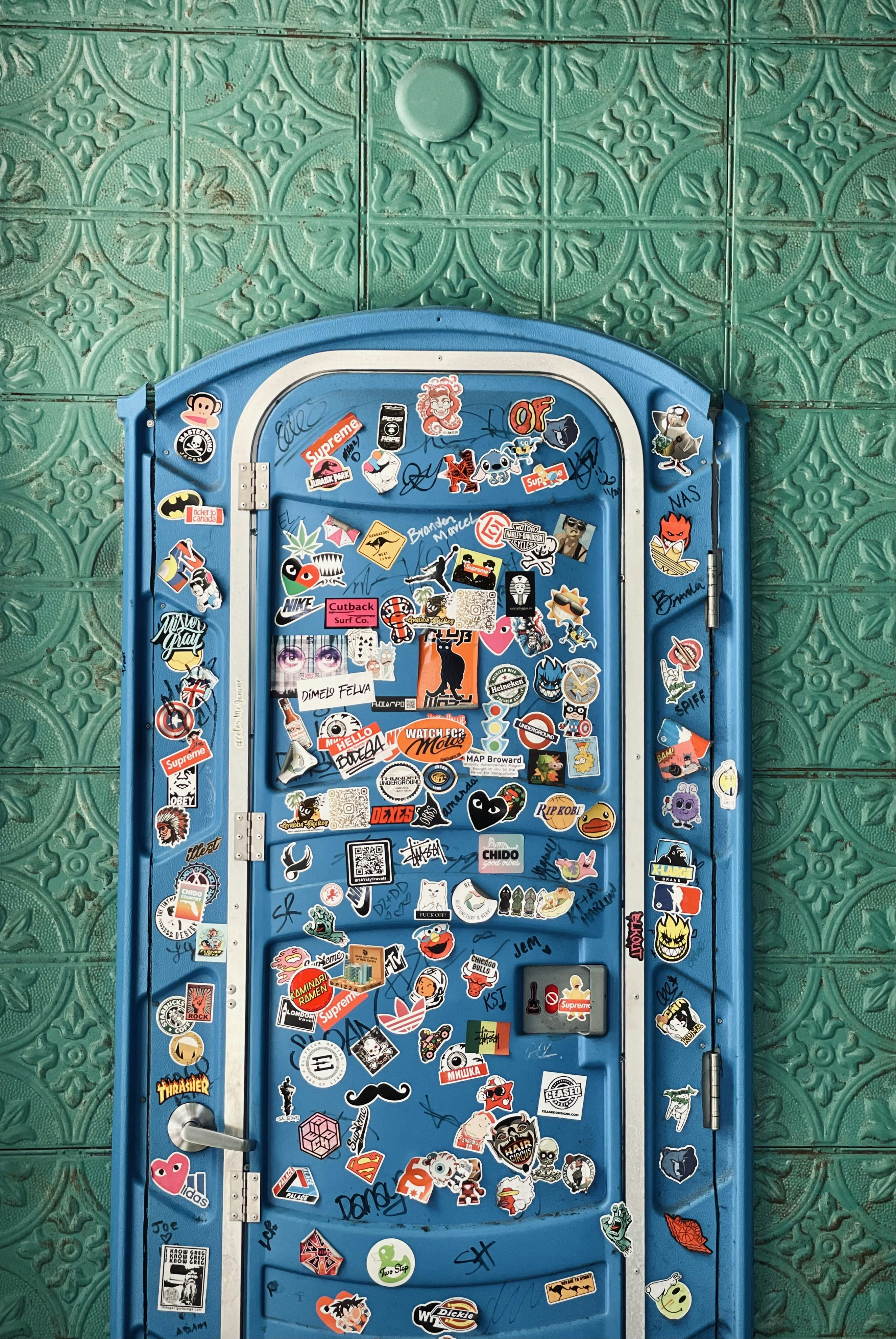 A blue refrigerator covered in lots of stickers