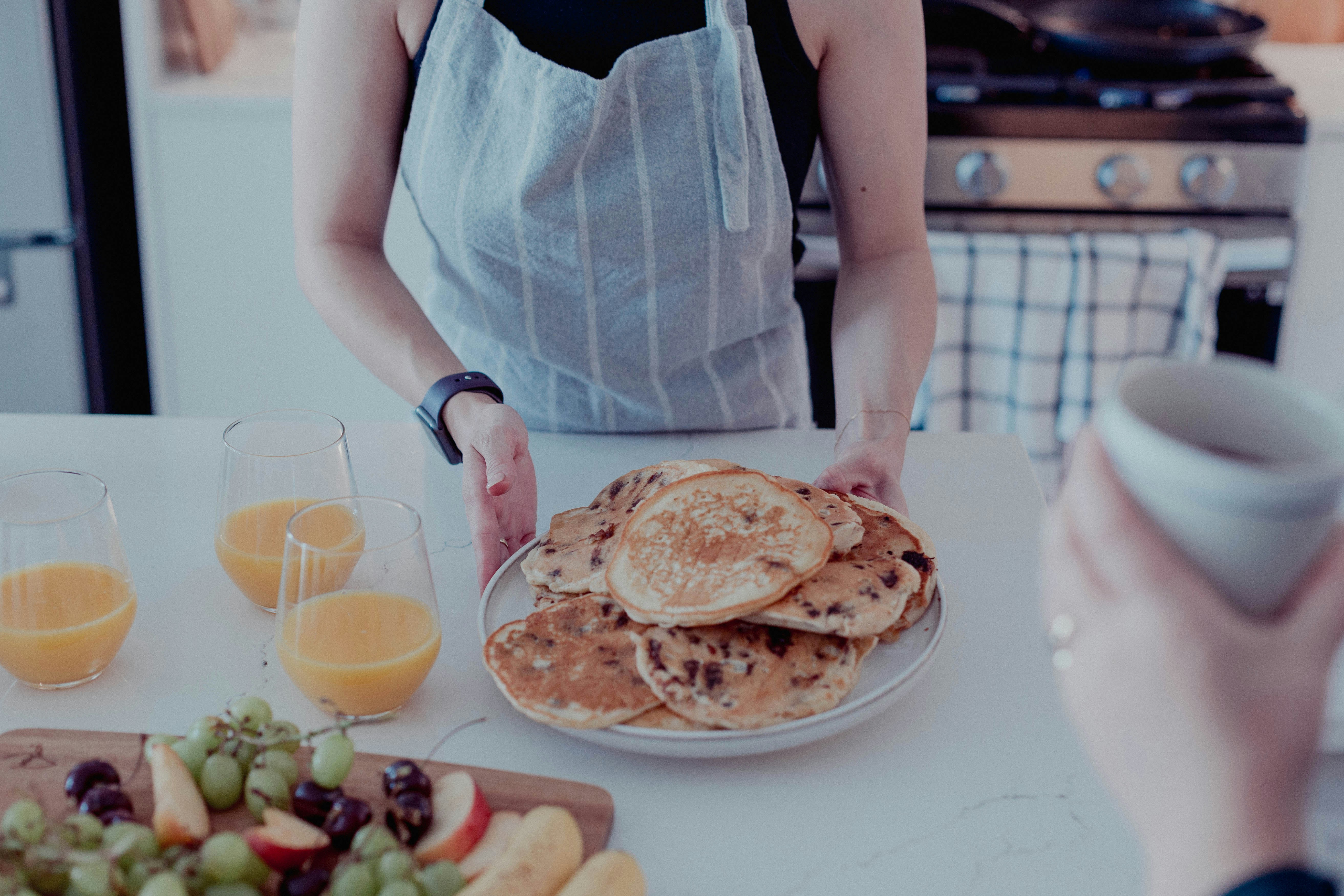 A woman standing in front of a plate of pancakes photo – Free Brunch ...