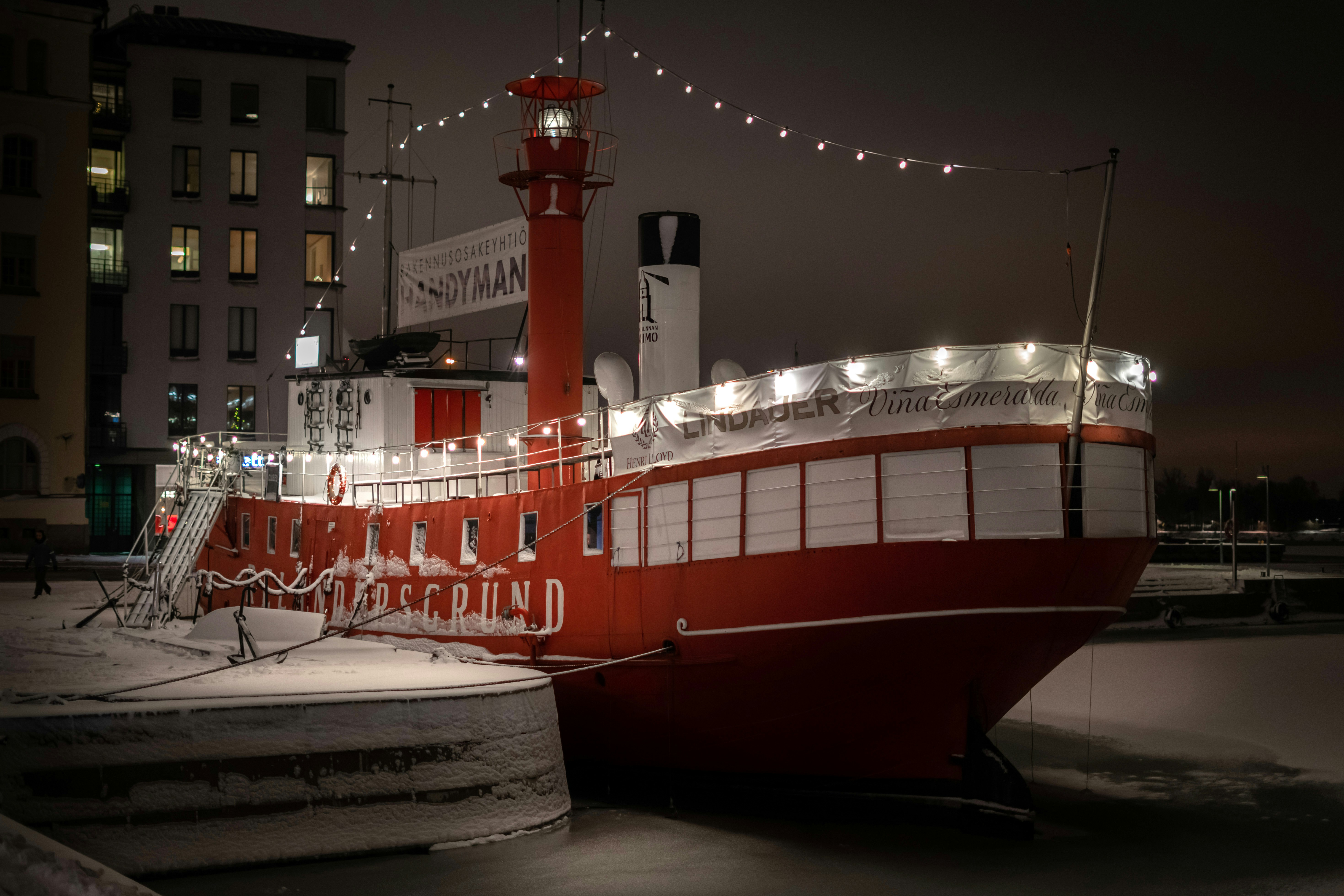 Crimson Vessel Dressed in Evening Lights at a Snowy Harbor