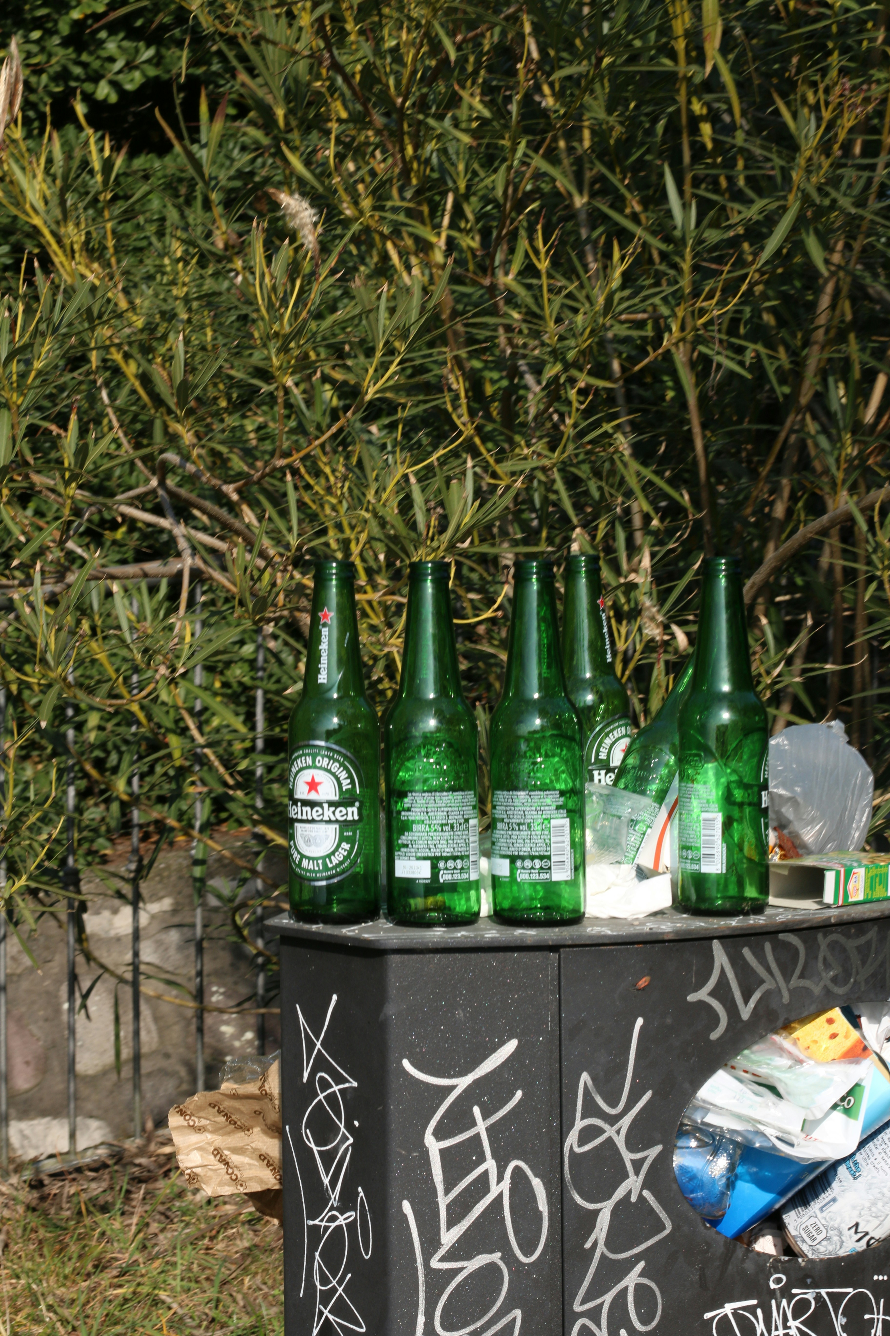Row of Heineken Bottles on a Graffiti-Streaked Stand at Dusk