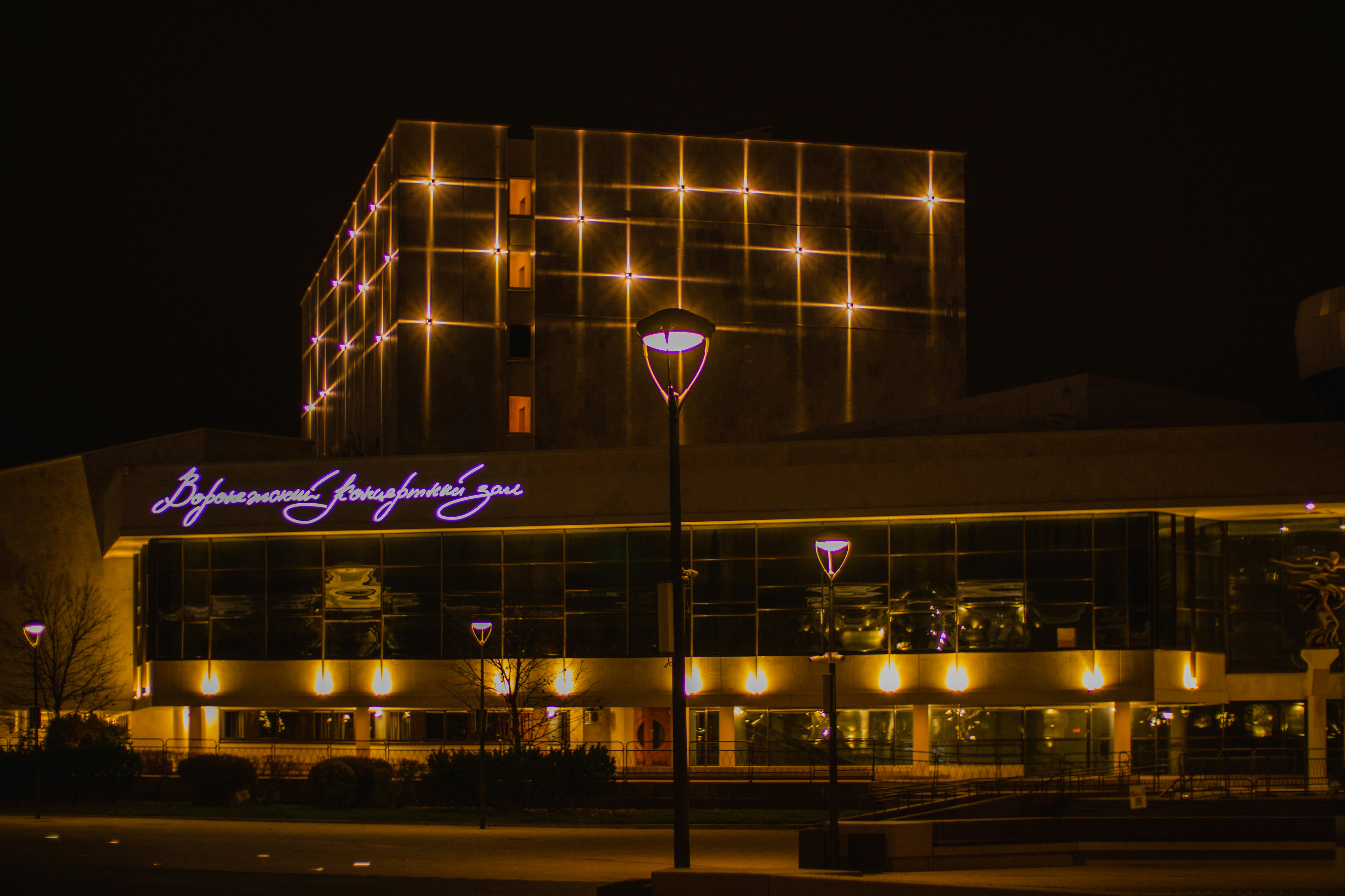 Night view of a hotel with warm lights illuminating the facade and geometric grid patterns.