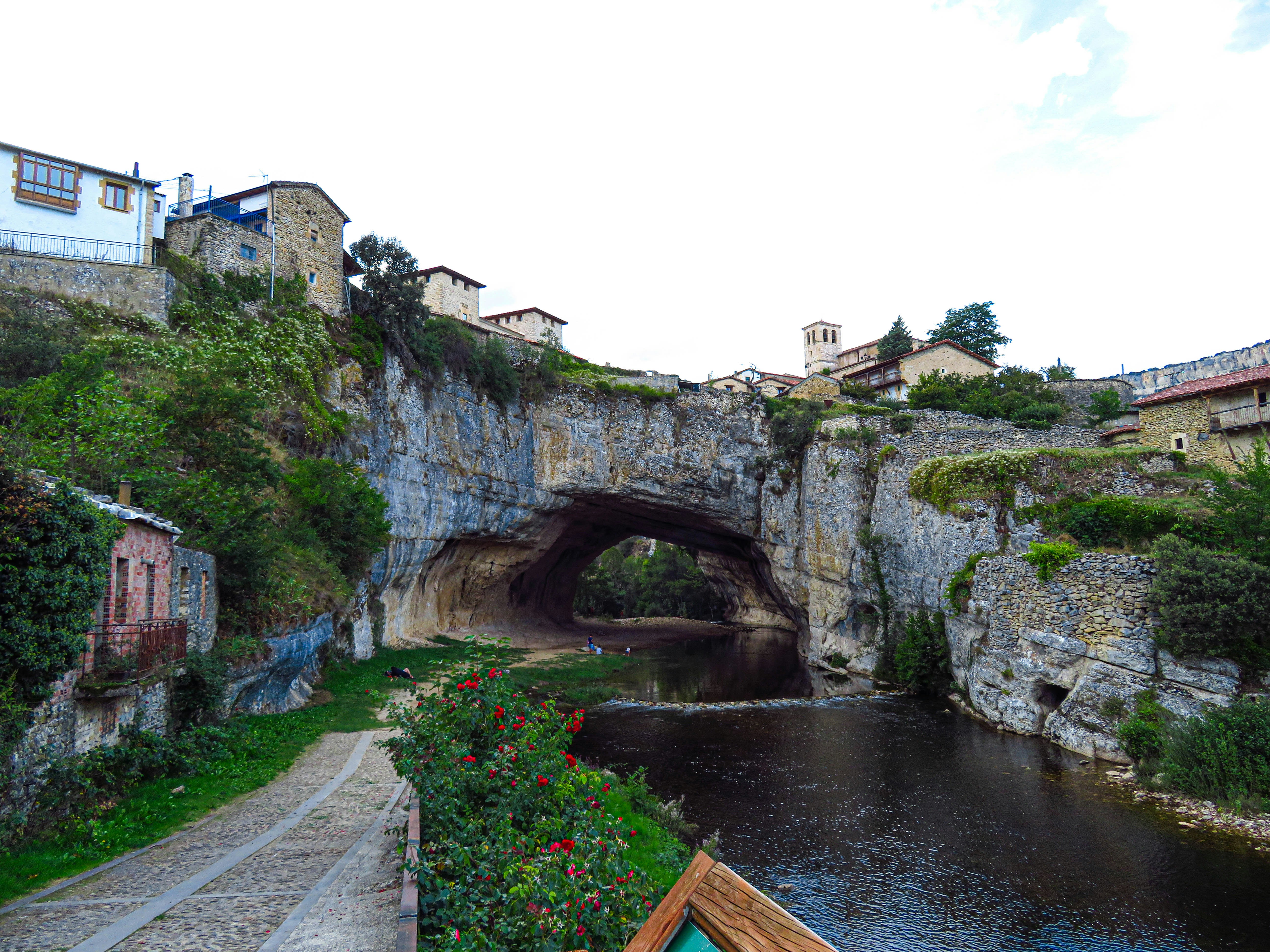 Stone Archway Over a Quiet River, Framed by Greenery and Cobbled Path