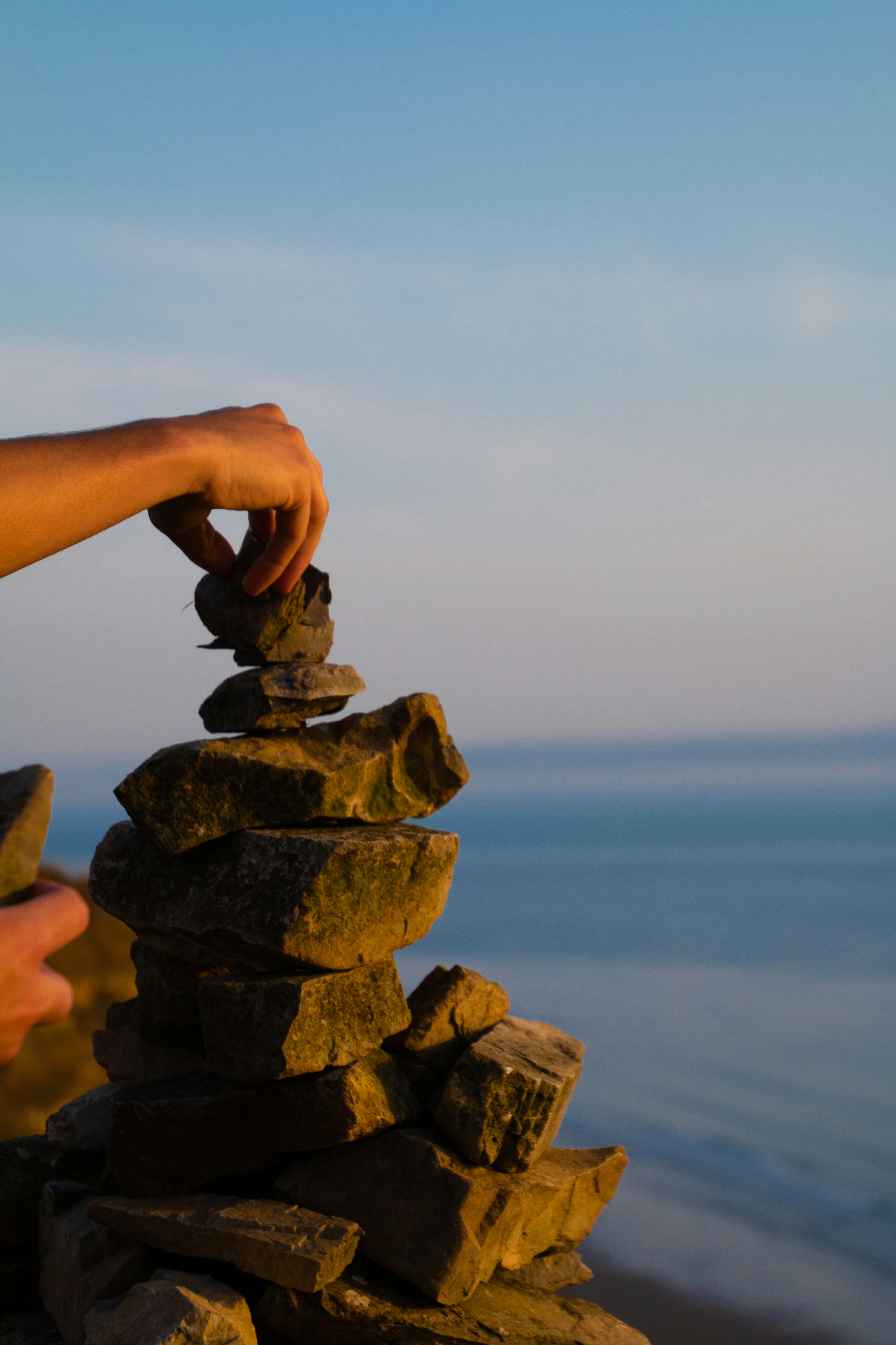A person stacking rocks on top of a beach photo – Free Beach Image on ...