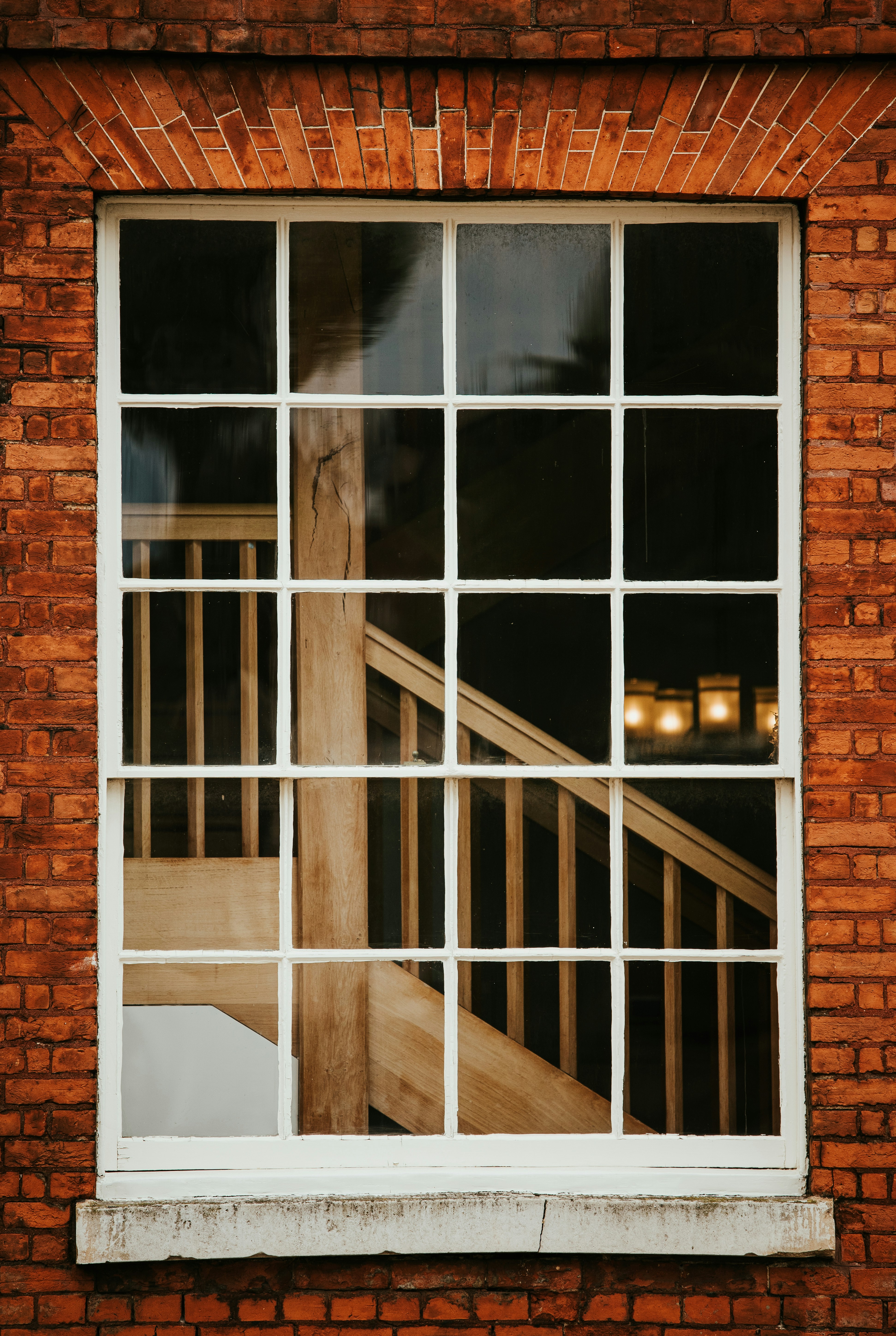 Brick-Framed Window: A Wooden Staircase Unfolds Behind Glass