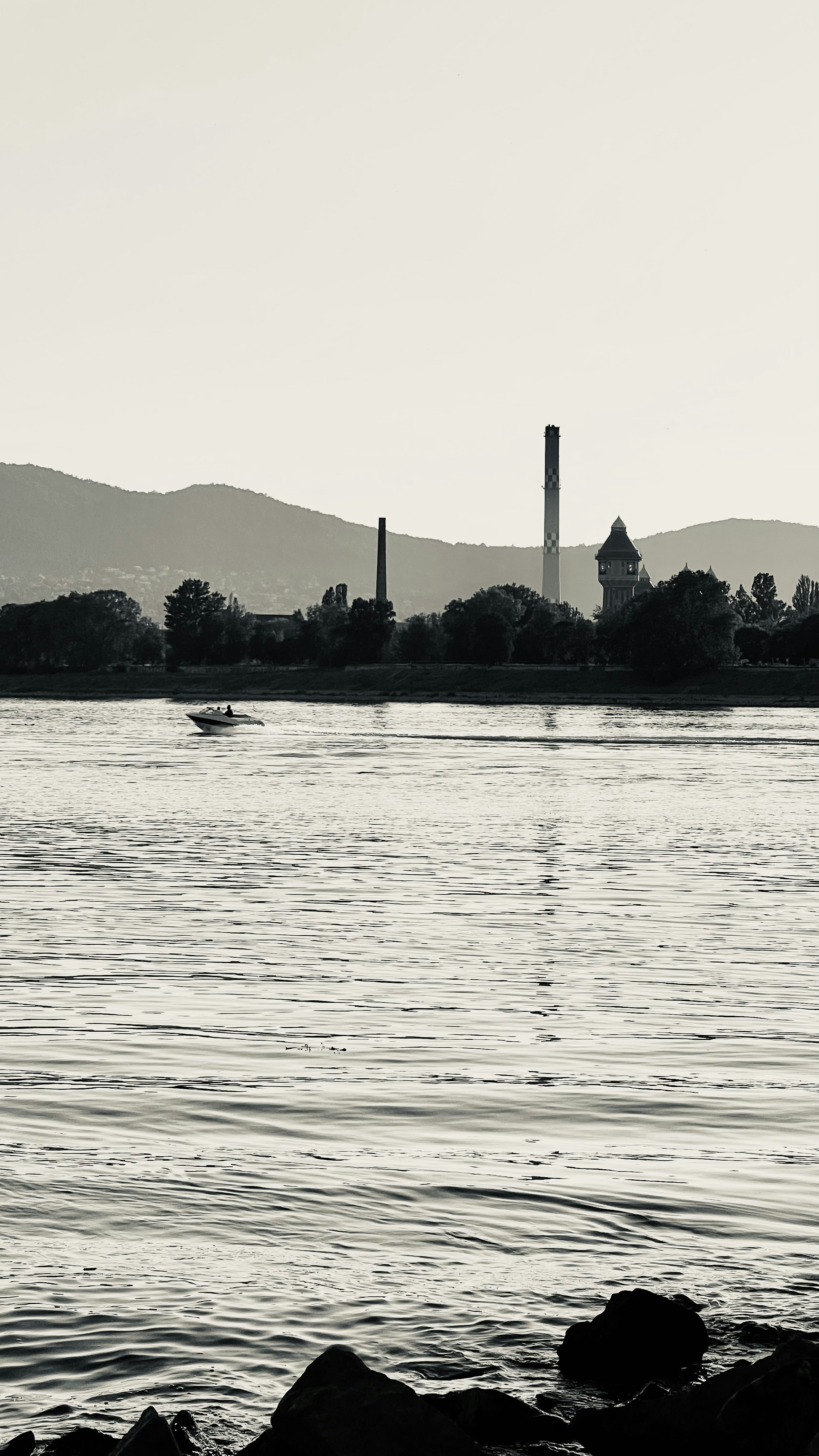 Industrial silhouette across a calm river at dusk